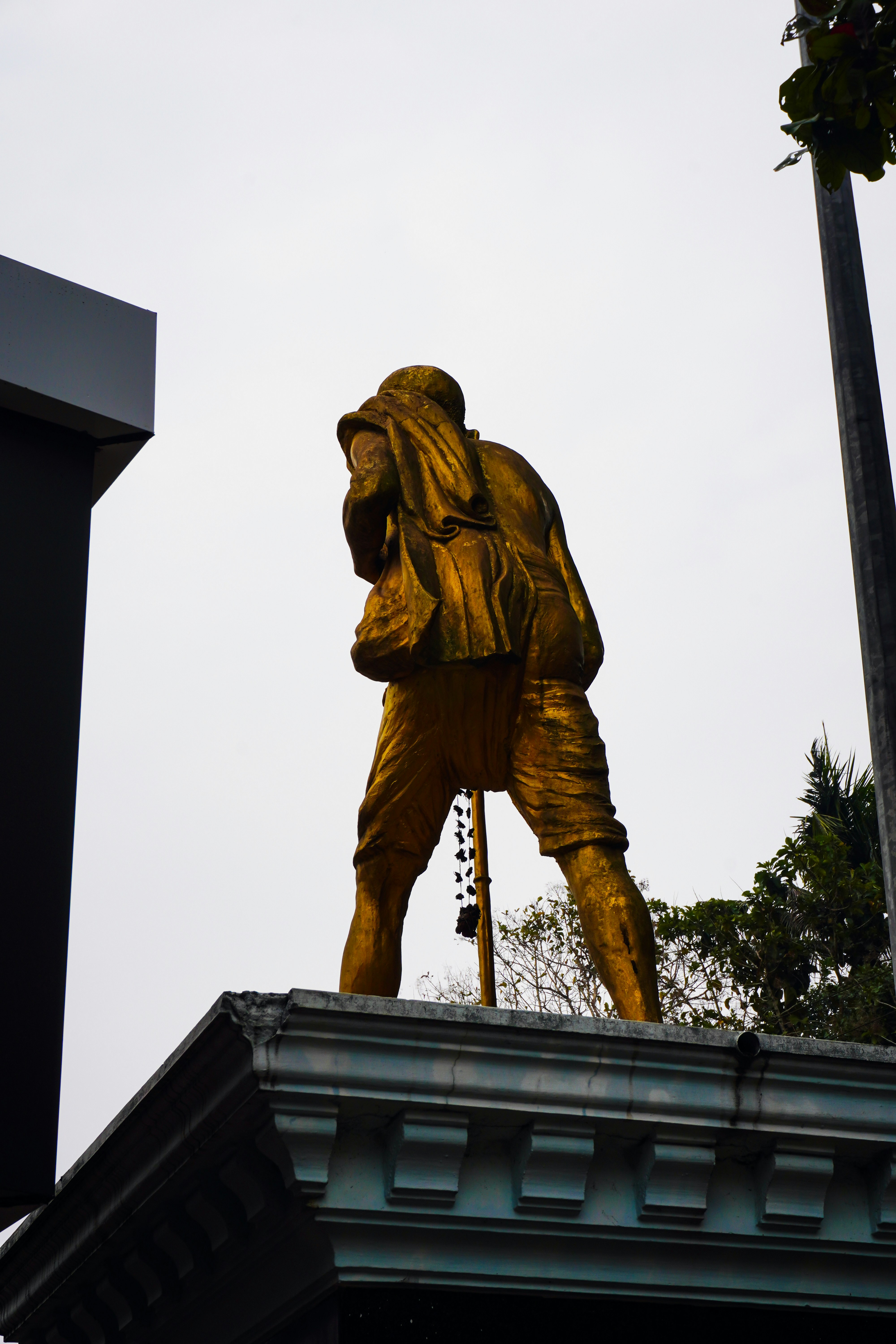 Golden Figure on a Rooftop: A Quiet Stand Under Overcast Sky