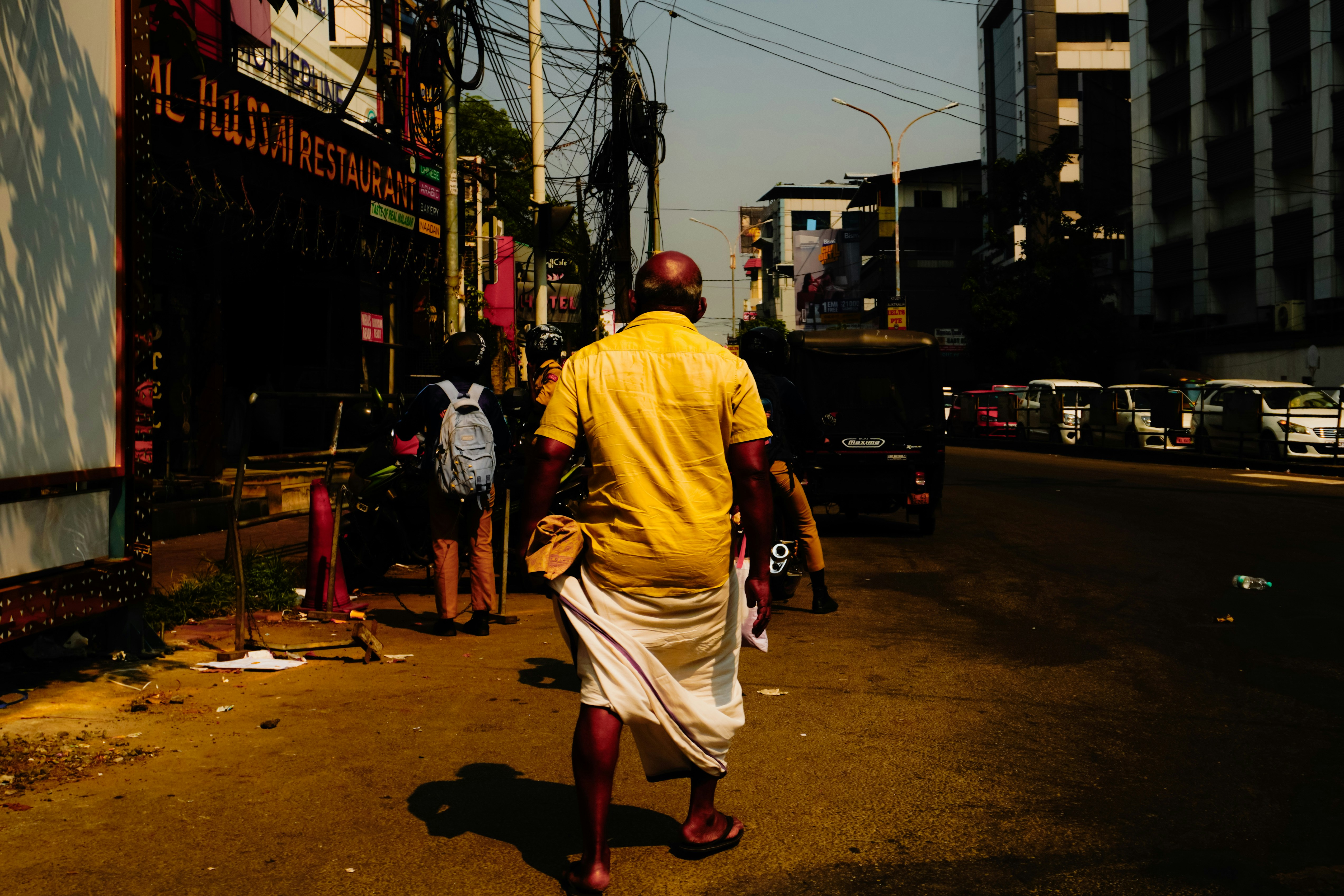 Yellow-shirted Pedestrian Crossing the Sunlit Urban Street