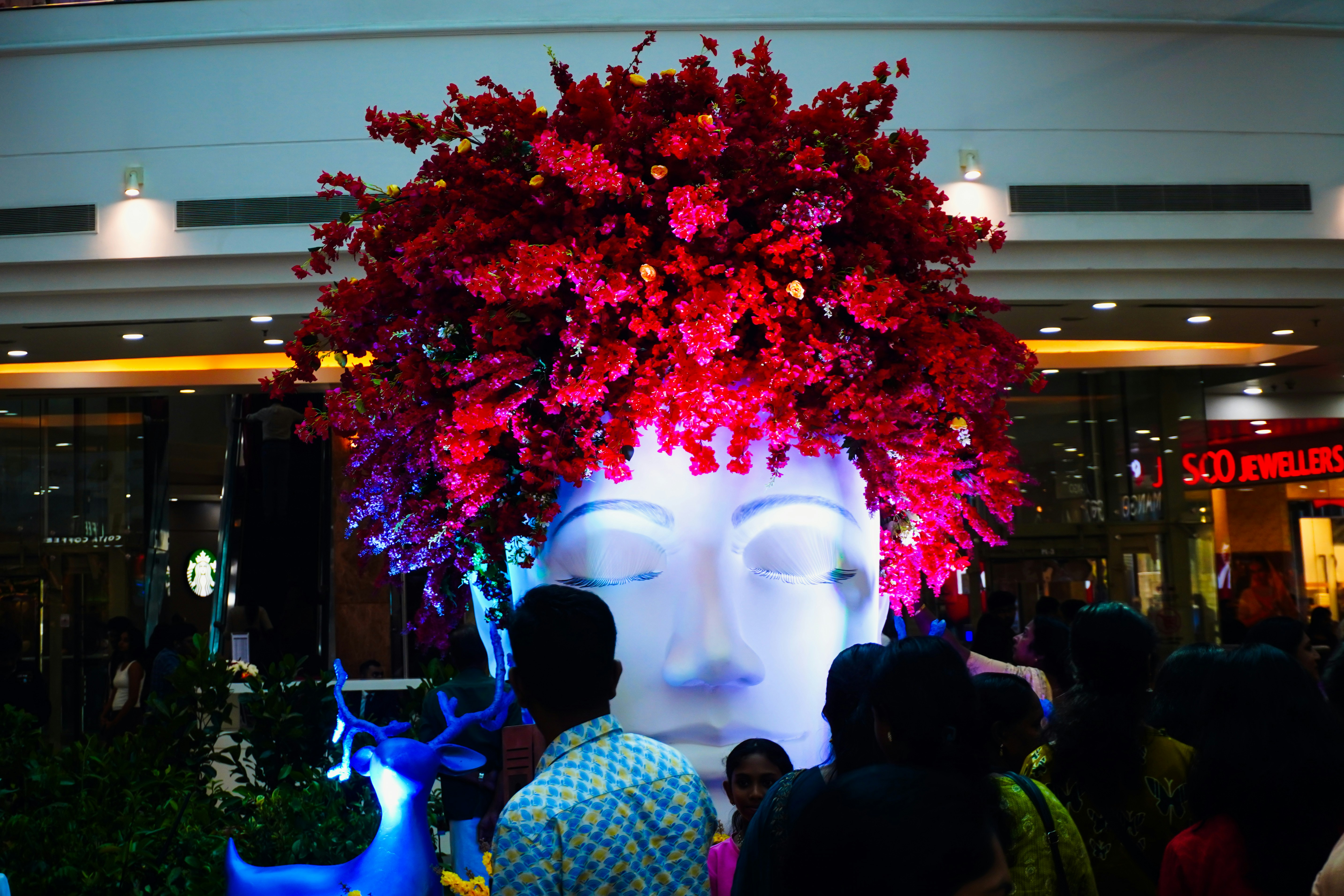 Floral Carnelian: A Giant Serene Head Surrounded by People