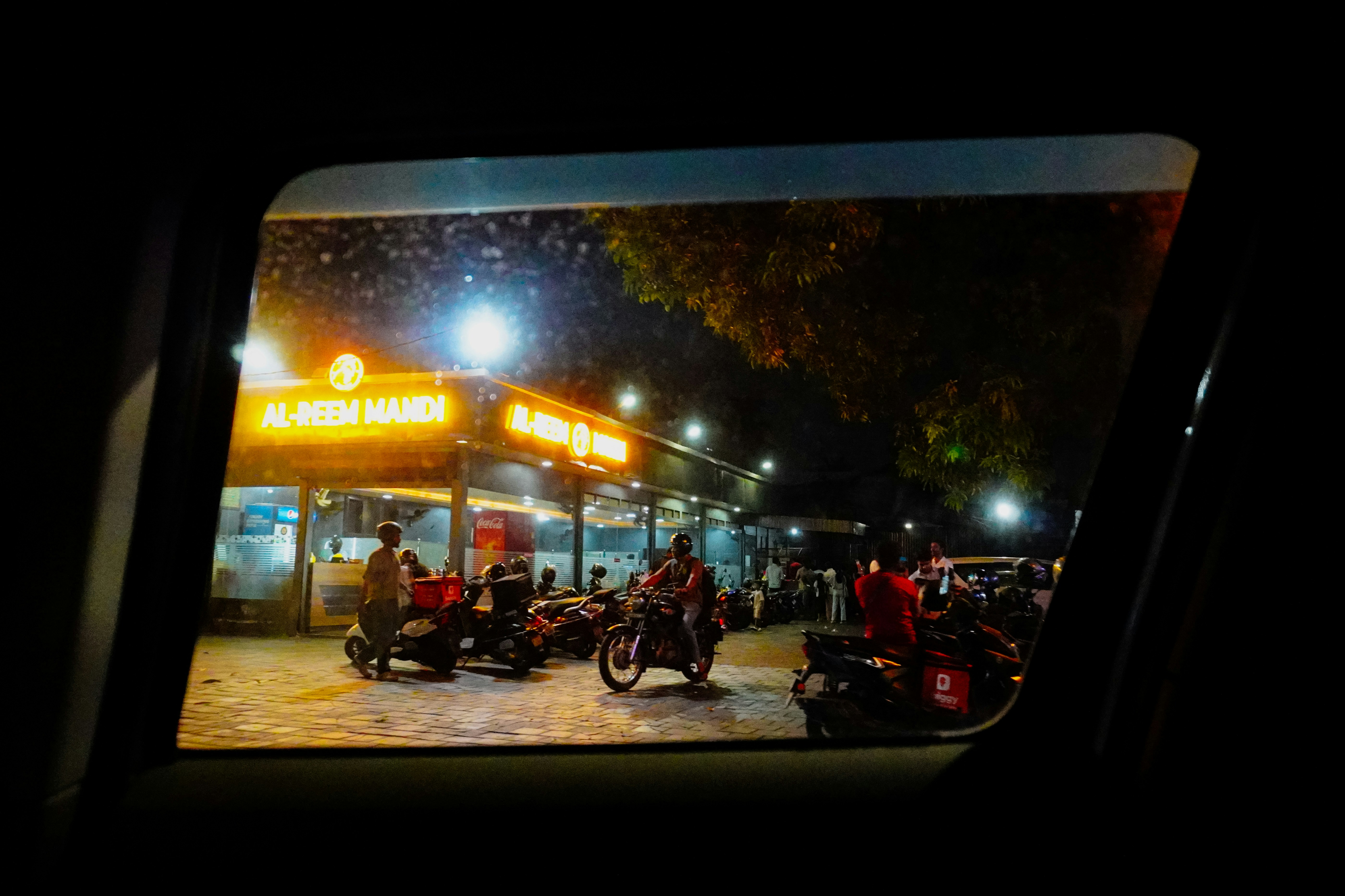 Night Market Stop: Neon Sign, Motorbikes, and Shaded Pedestrian Corridor