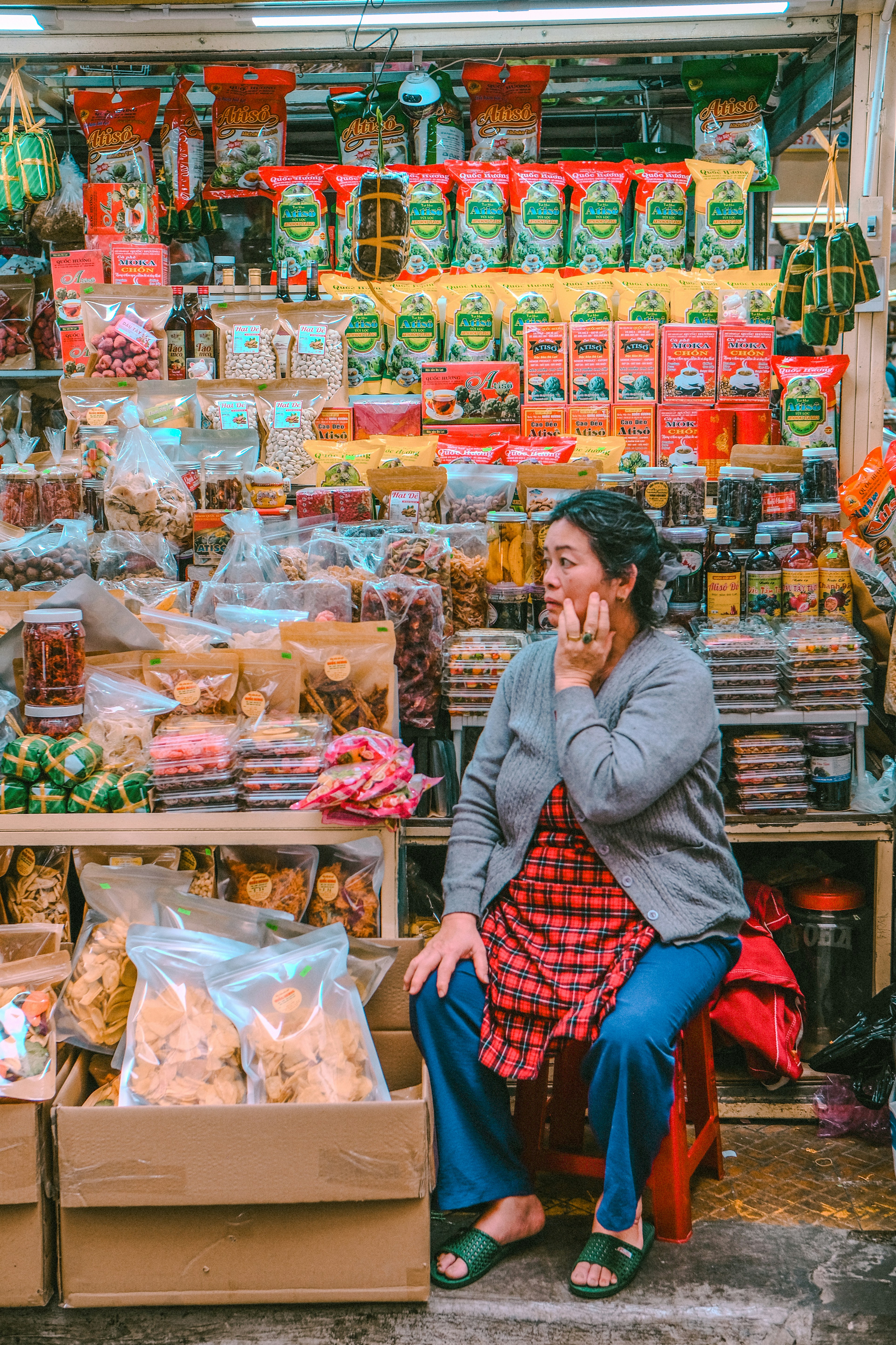 Market Portrait: A Woman Pauses Amid Colorful Snack Aisles