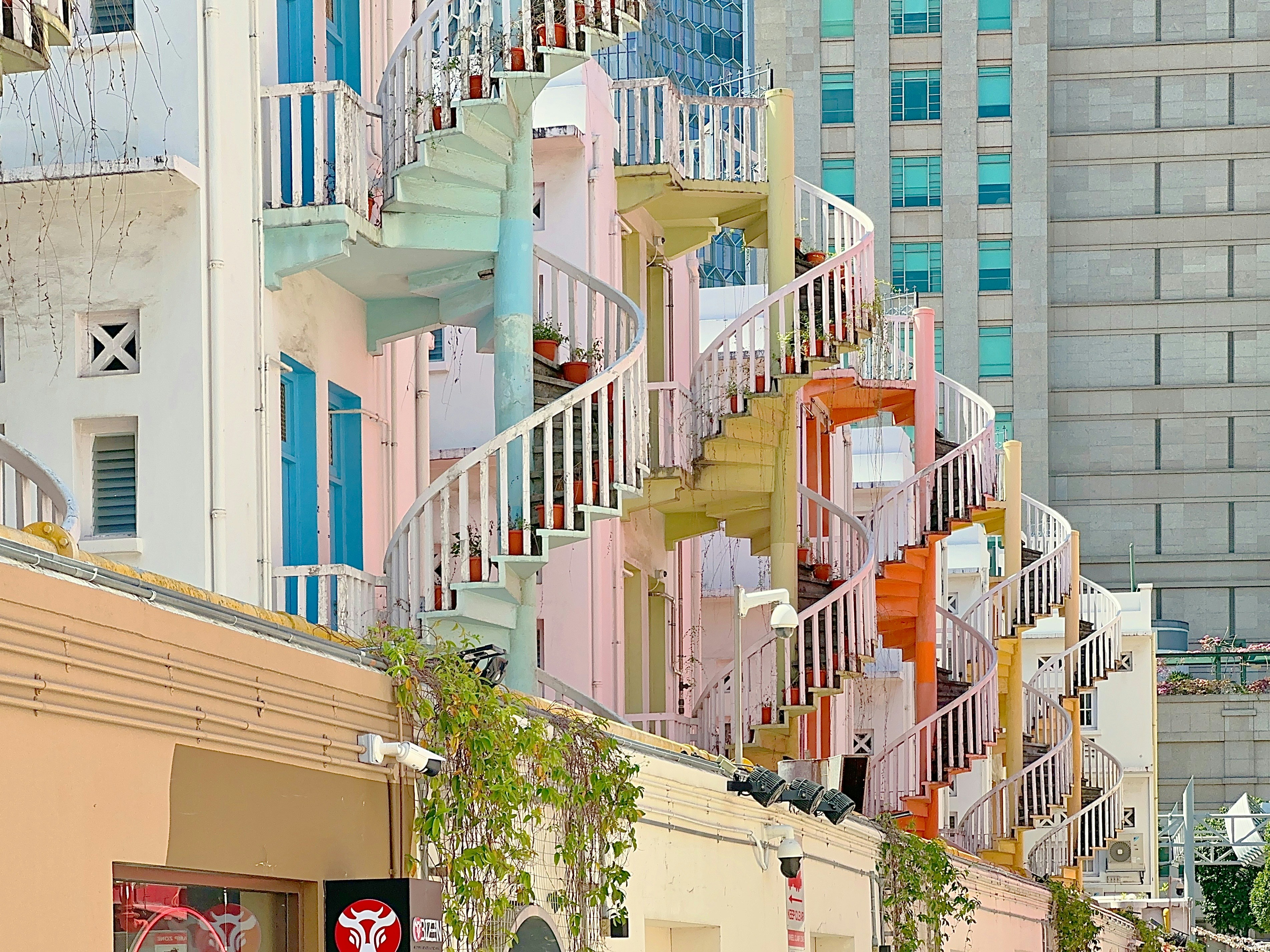Spiral stairway cascade through pastel apartment facades