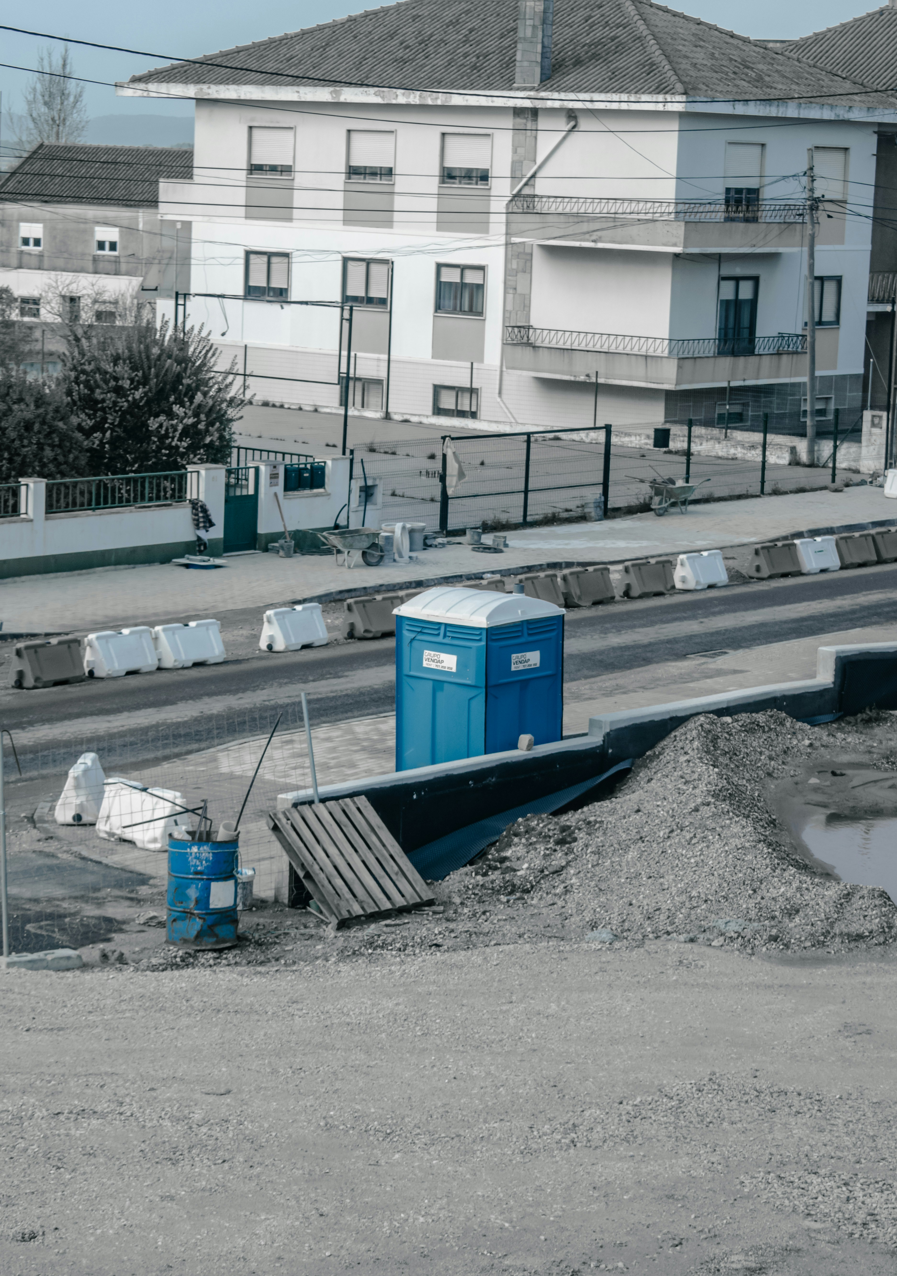 Blue Portable Toilet Among Urban Construction Debris