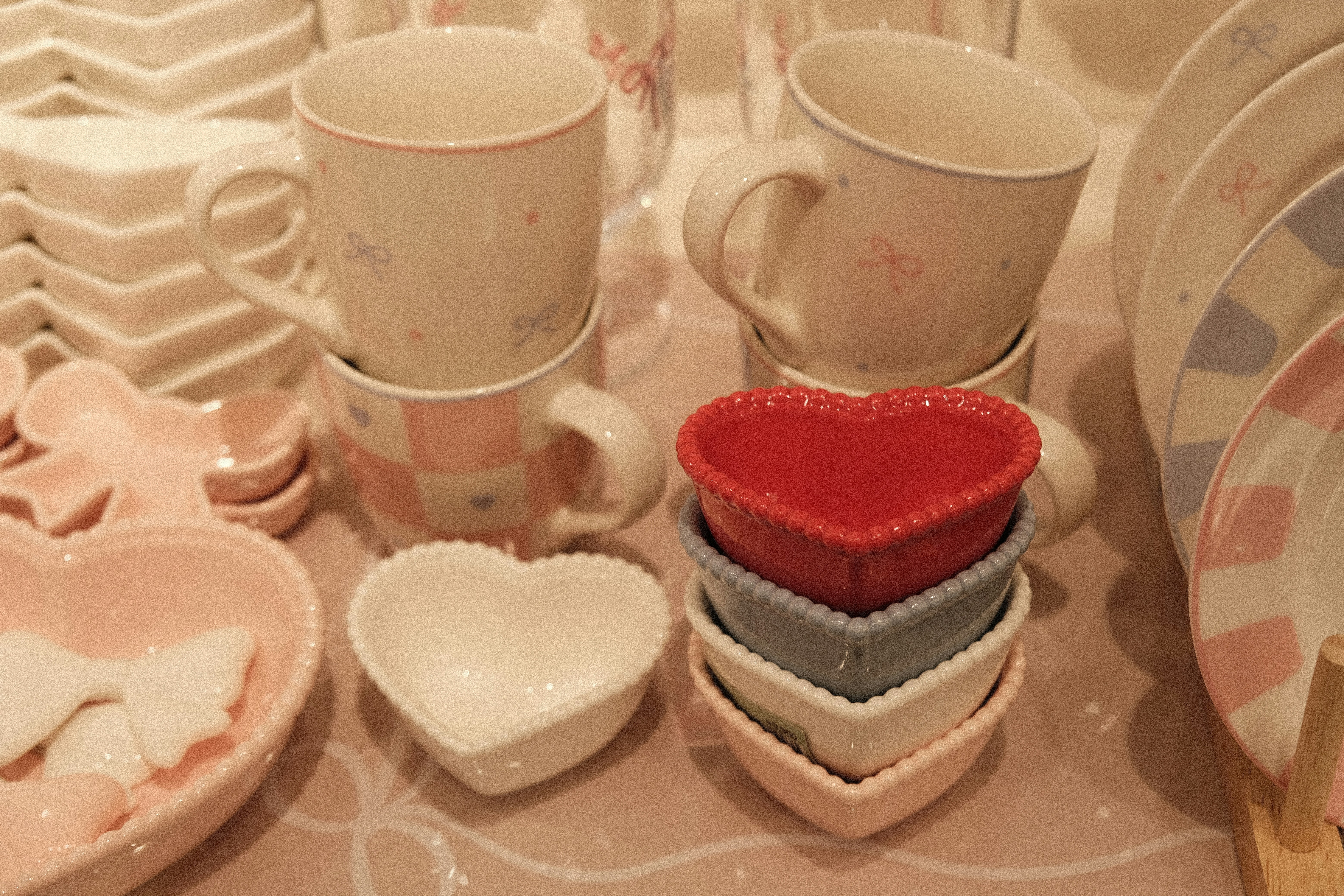 Stacked pastel heart bowls under pastel mugs on a dessert table