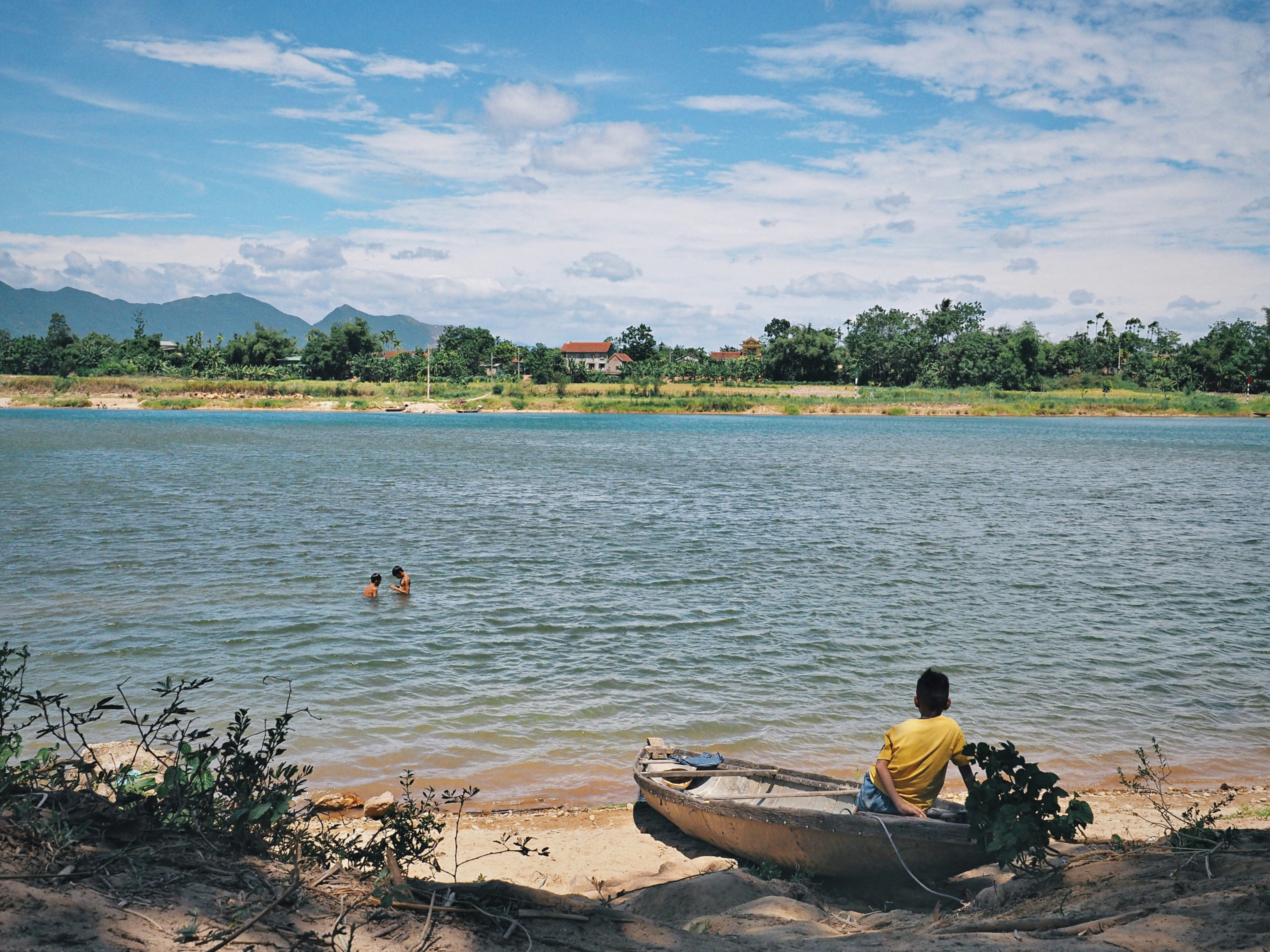 Boat with Child and Riverside Scene under Open Sky