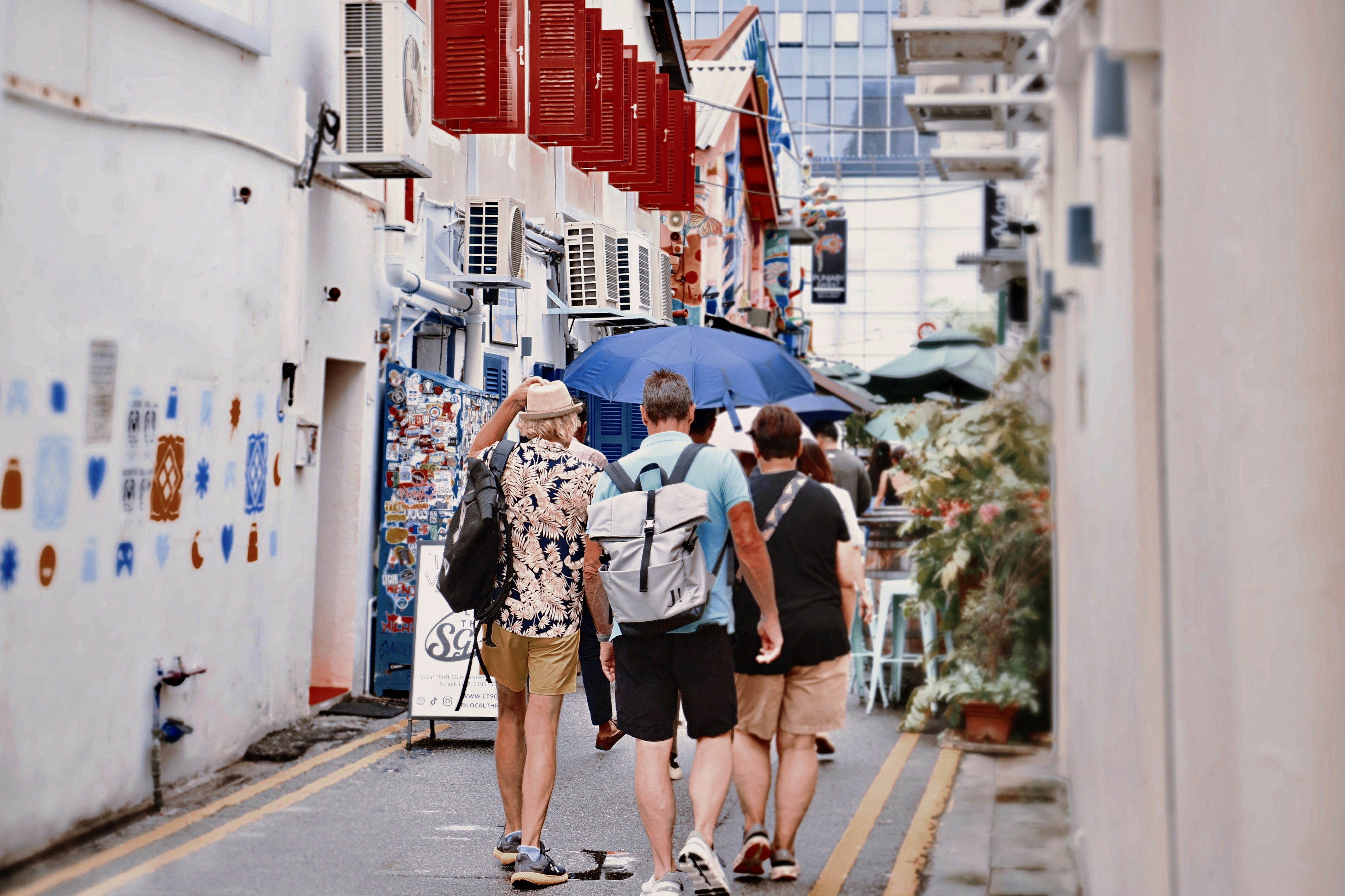 Umbrella Crossing: Friends in a Sunlit Alley