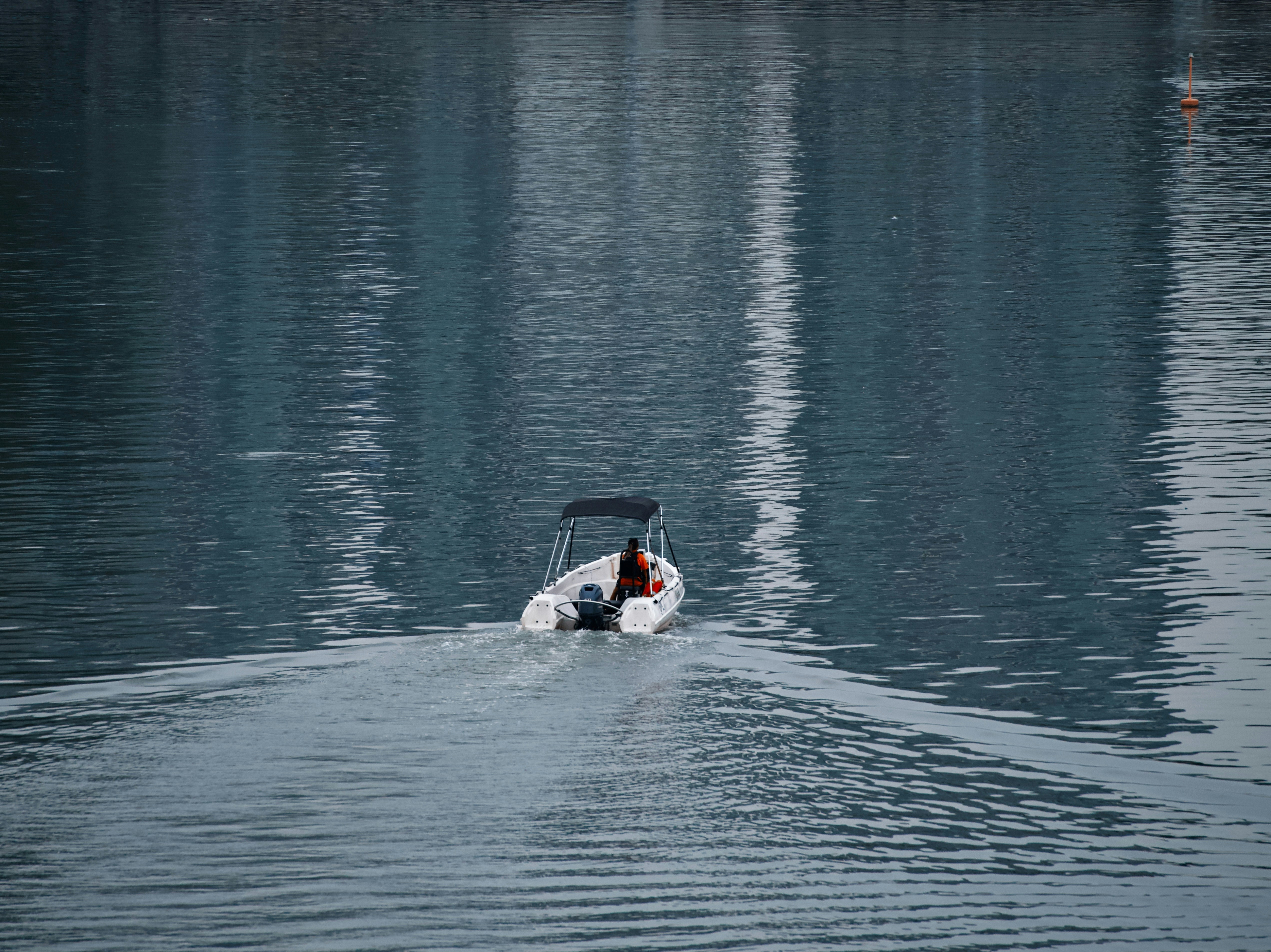 Boat Slipping Across Calm Harbor: Wake Lines Converge