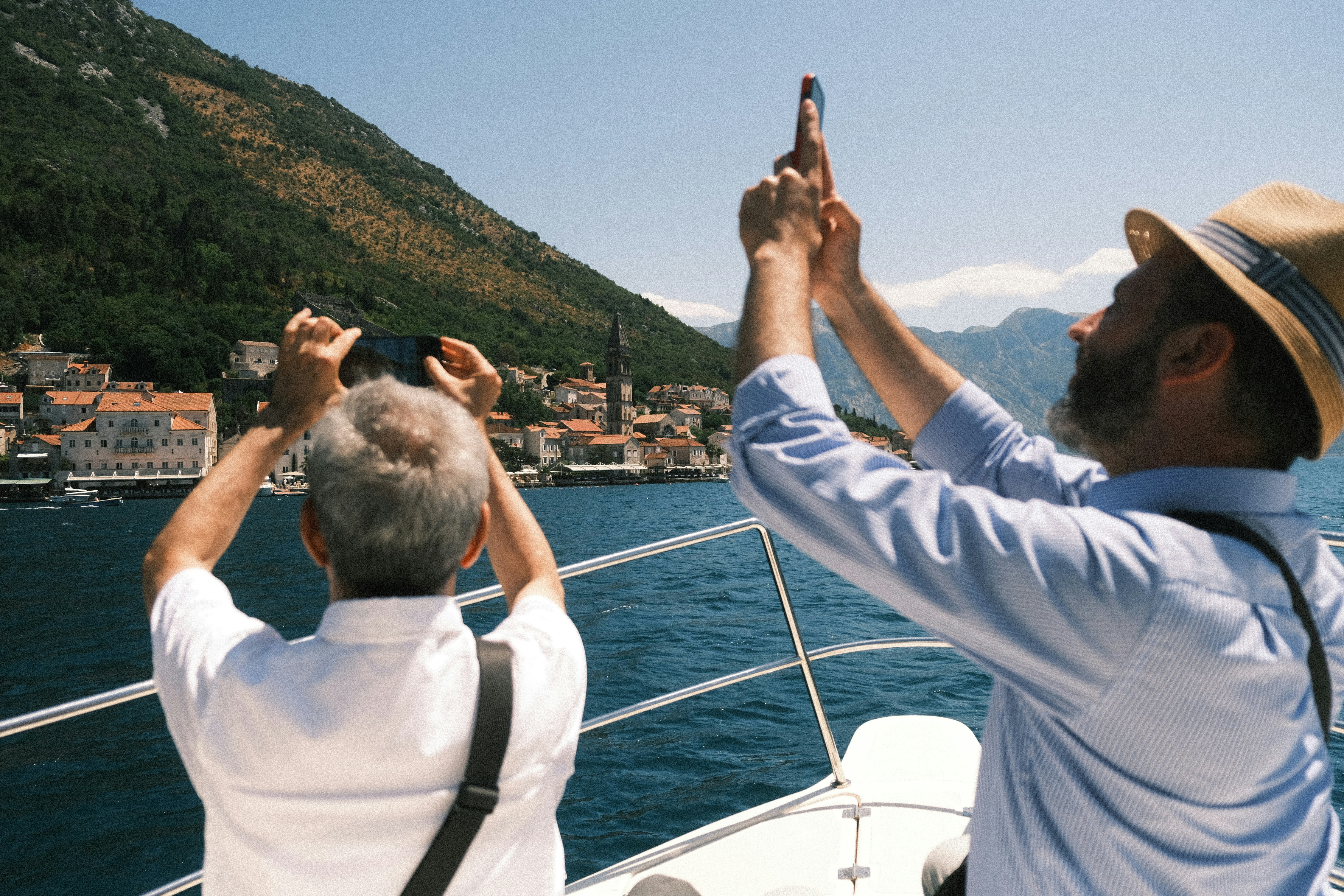 Two Tourists Capture the Harbour Village from a Sunlit Deck