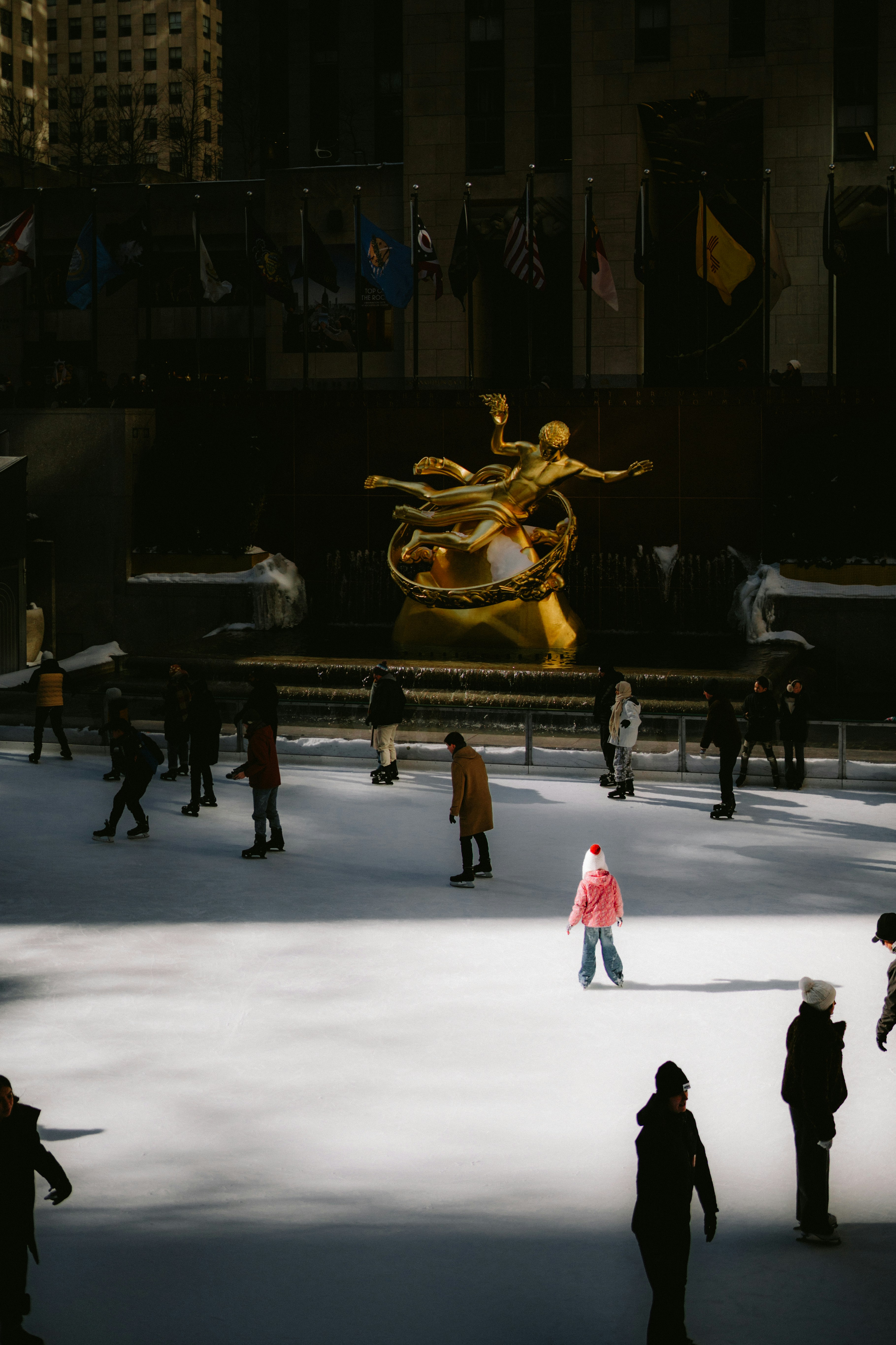 Golden Statue Under Ice: An Alley of Skaters with a Sunlit Spotlight