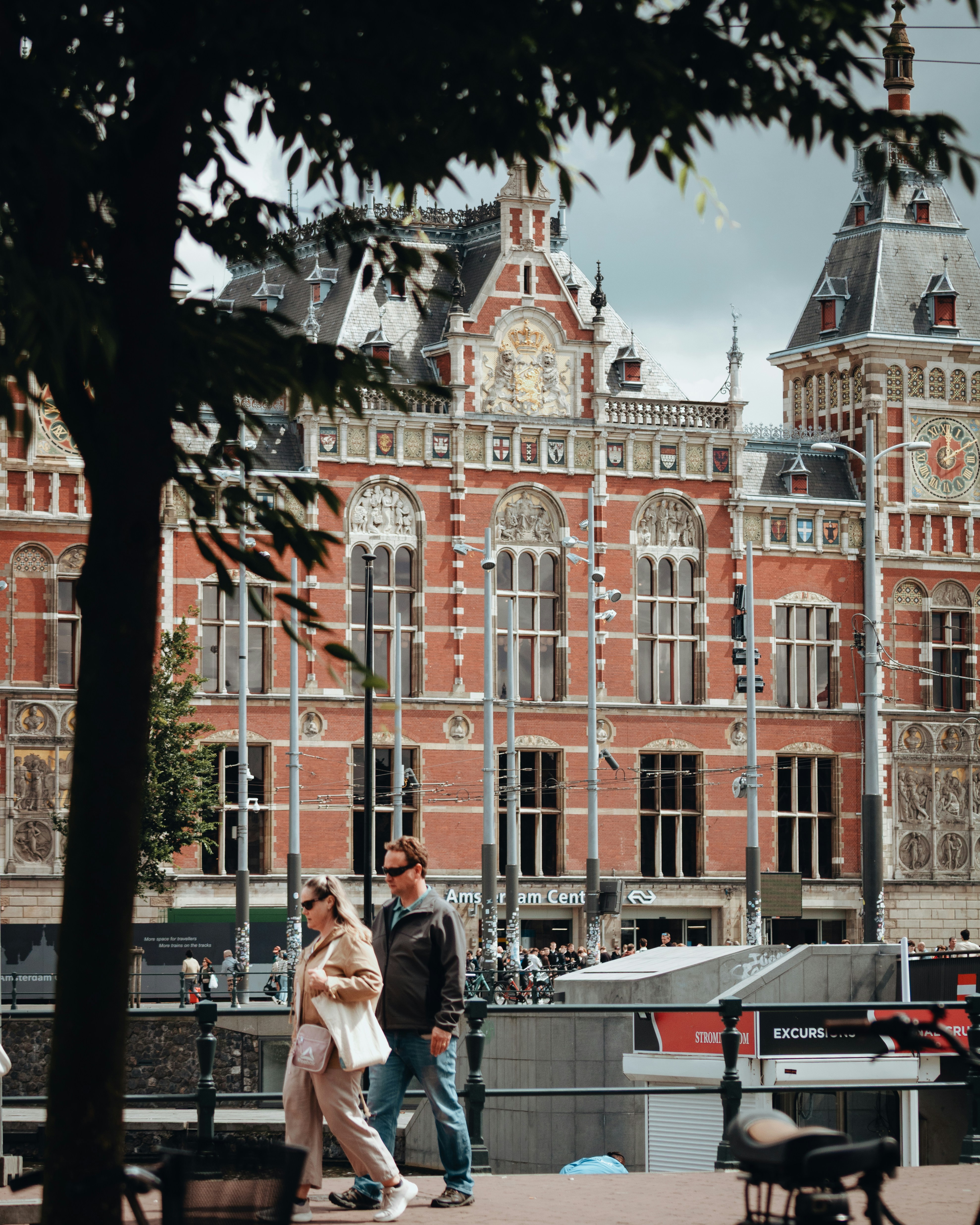 Baroque Facade Dialogue: Pedestrians in Front of Amsterdam’s Gilded Brick