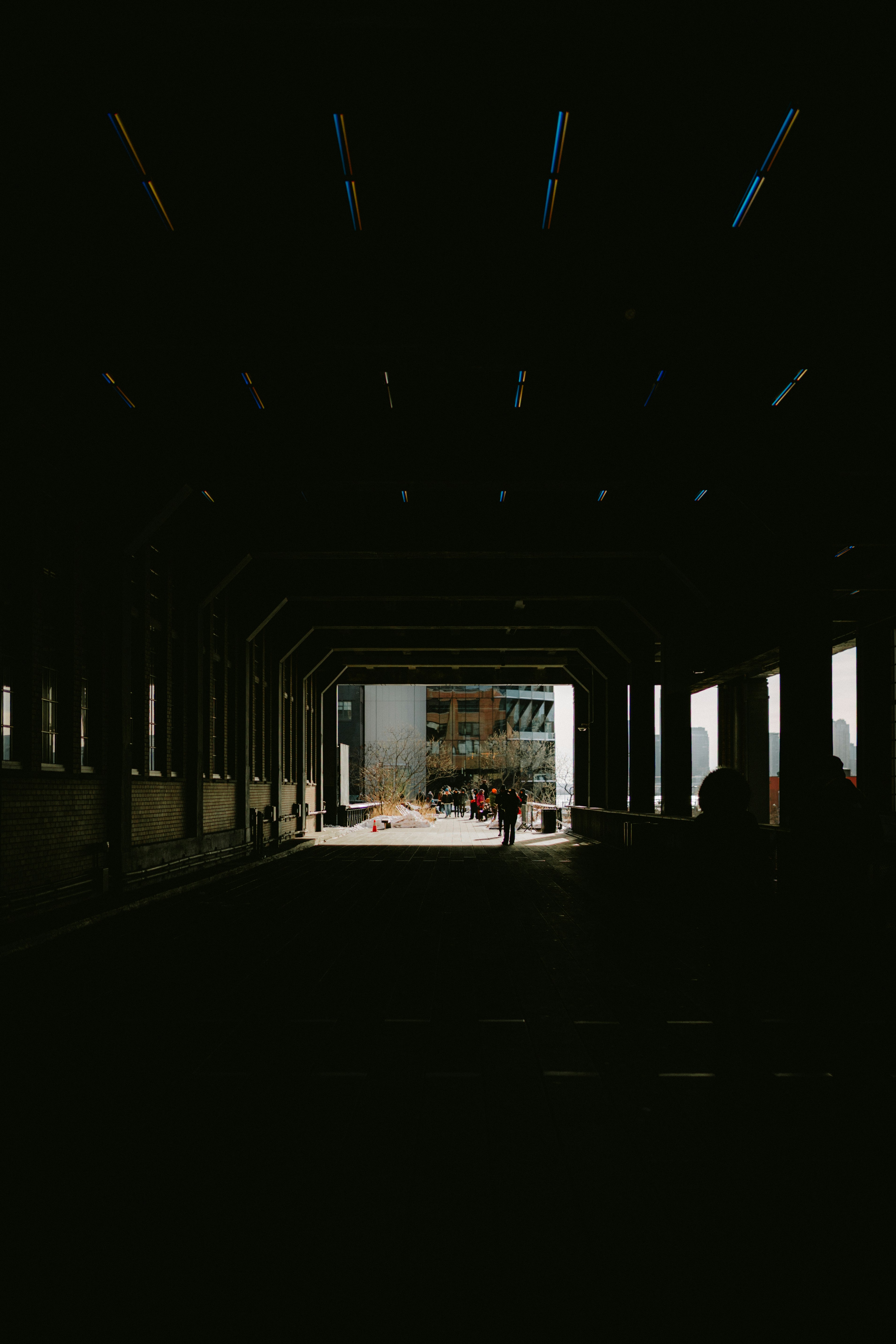 Light at the Terrace End: People in a Sunlit Courtyard Framed by a Dark Corridor