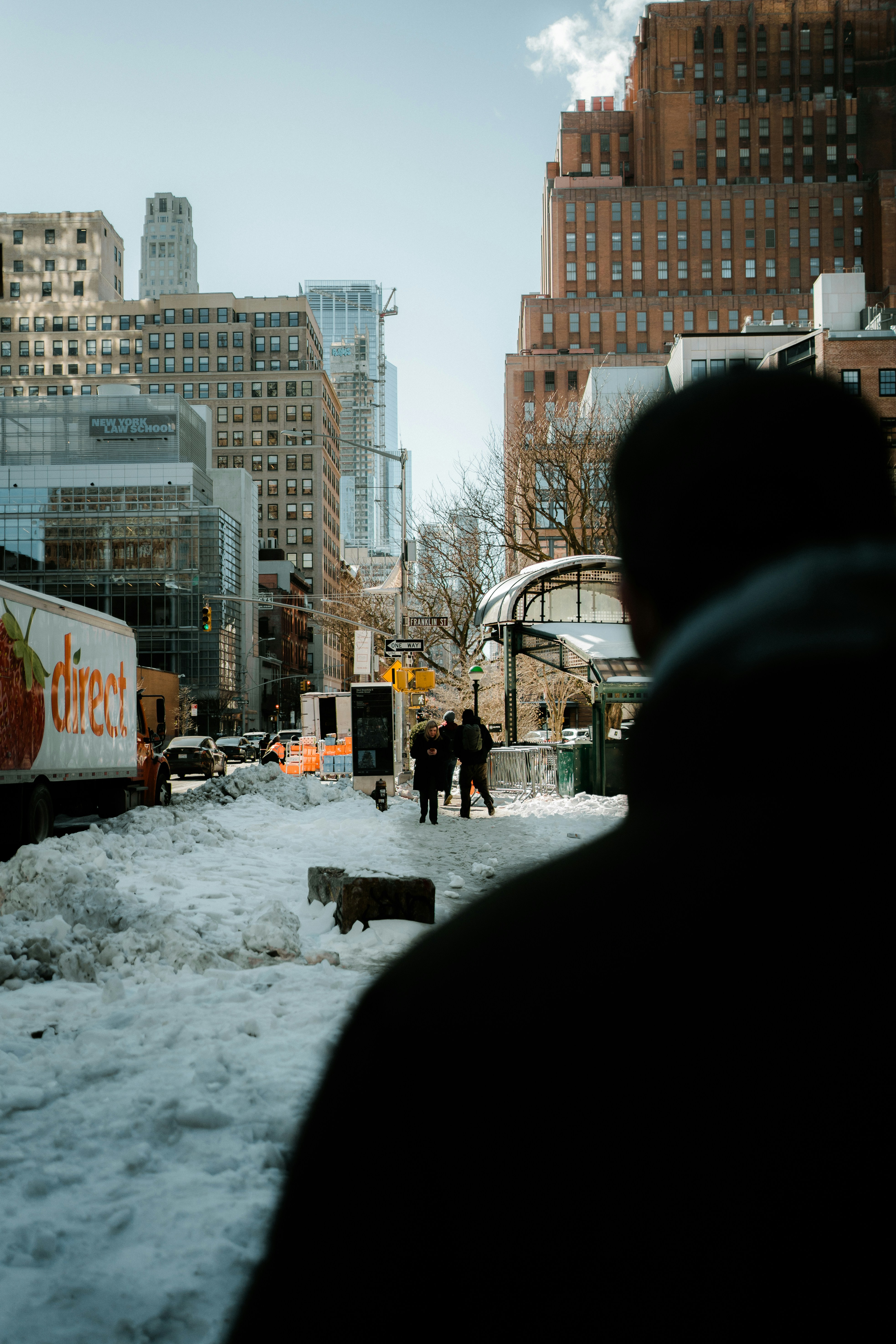 Snowy Manhattan Footpath: silhouettes, tram and rising towers