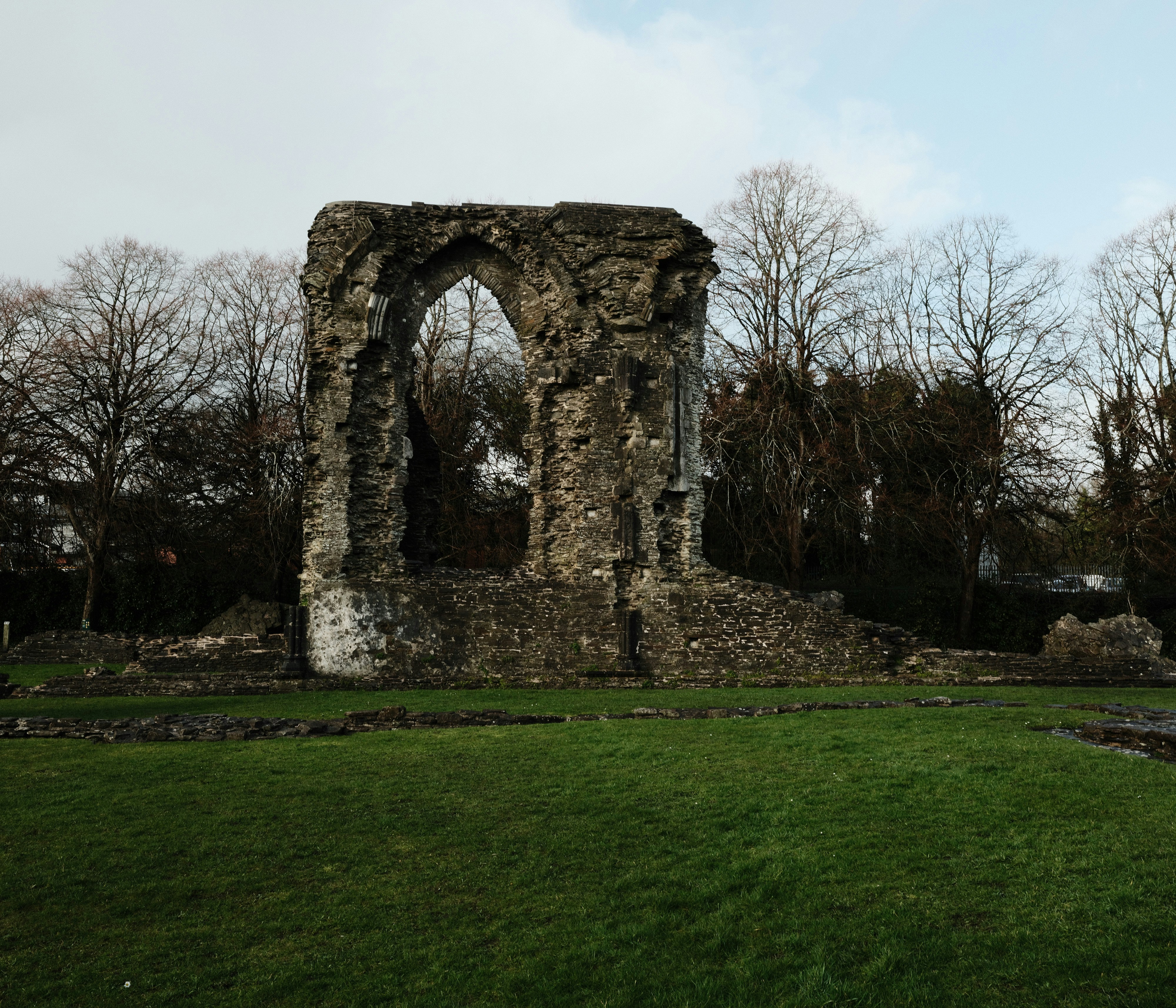 Ancient stone ruins with an arched window against trees