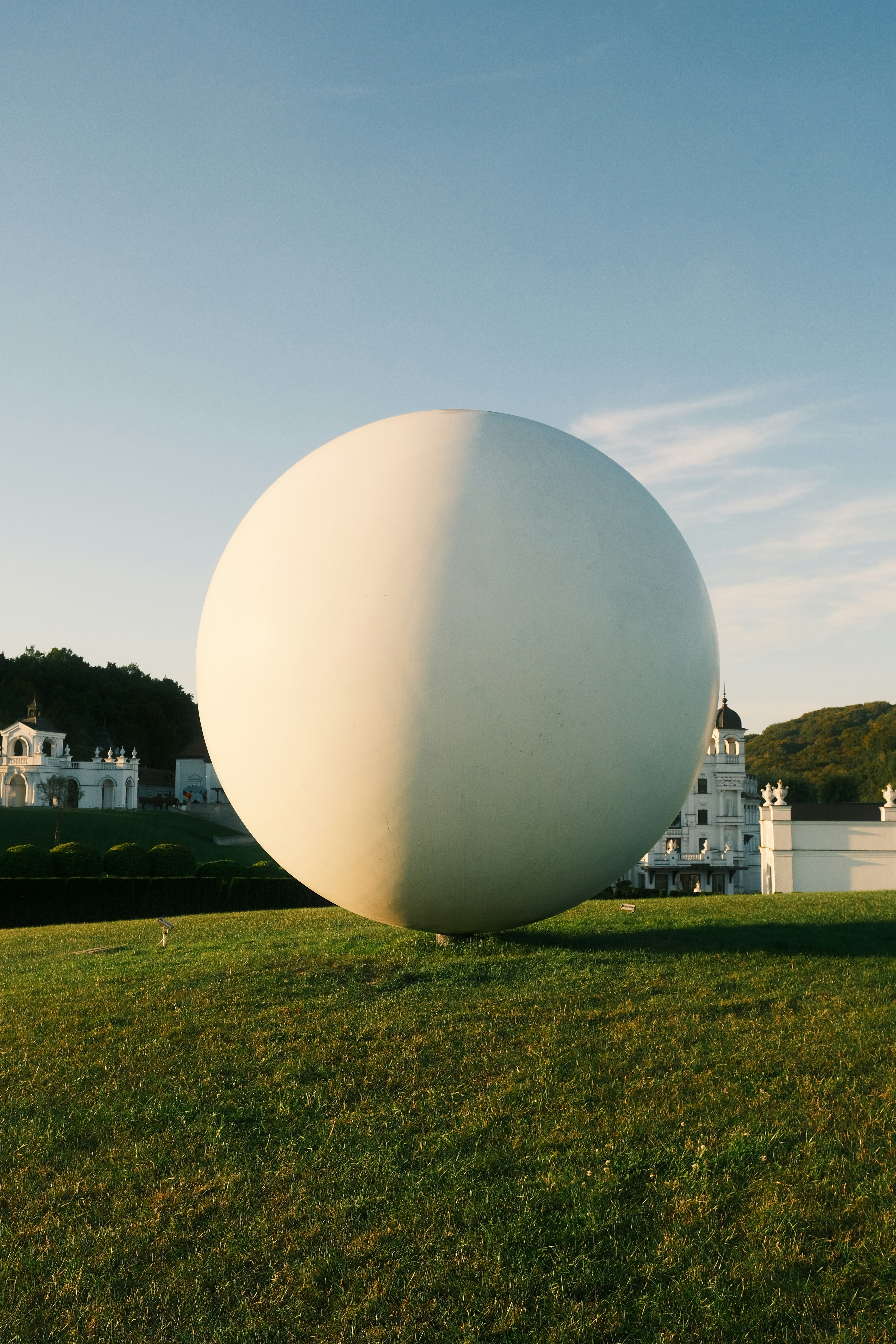 Moonlit Sphere: A colossal sculpture balanced on the lawn