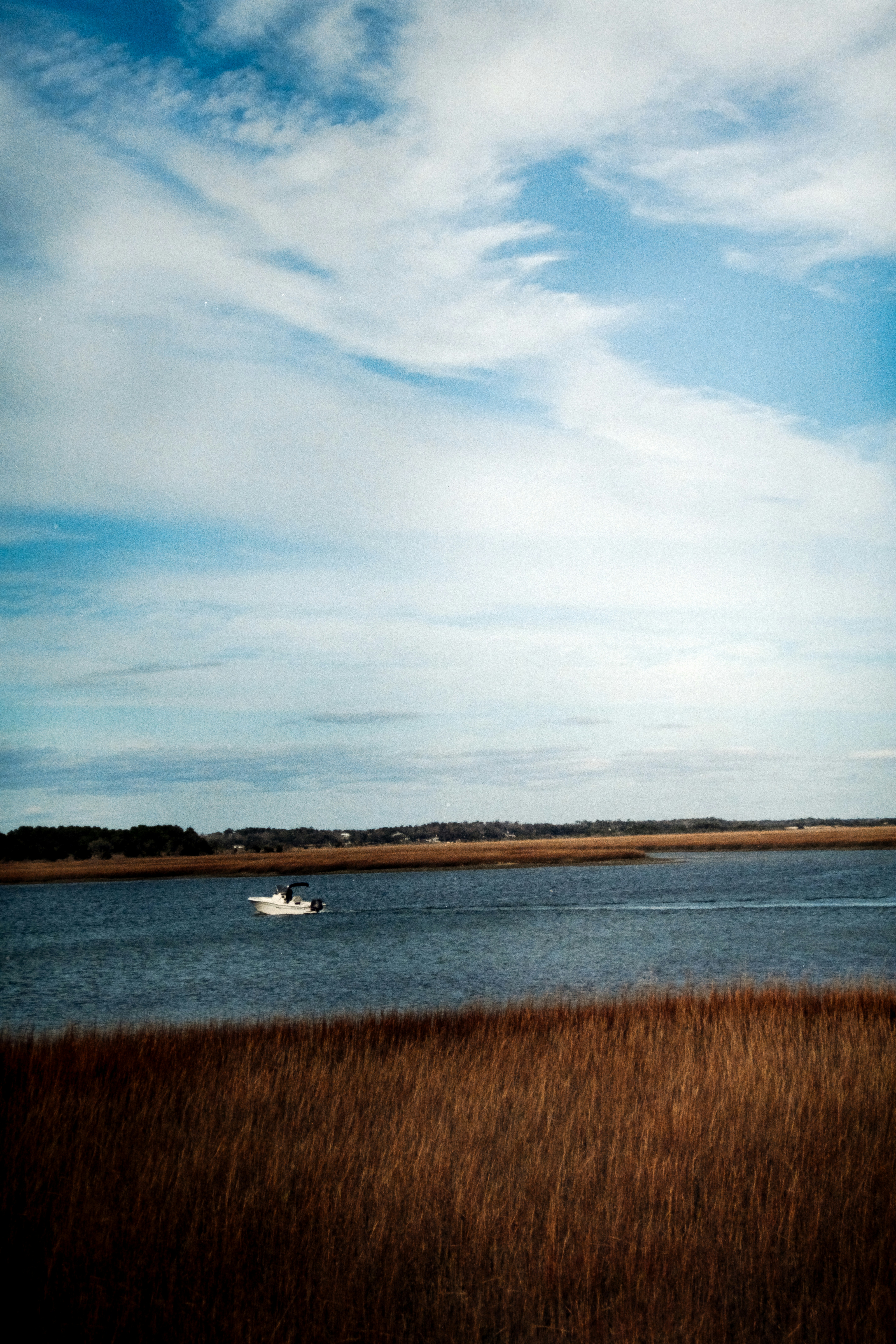 Boat Skimming Quiet Marsh Under Wide Sky