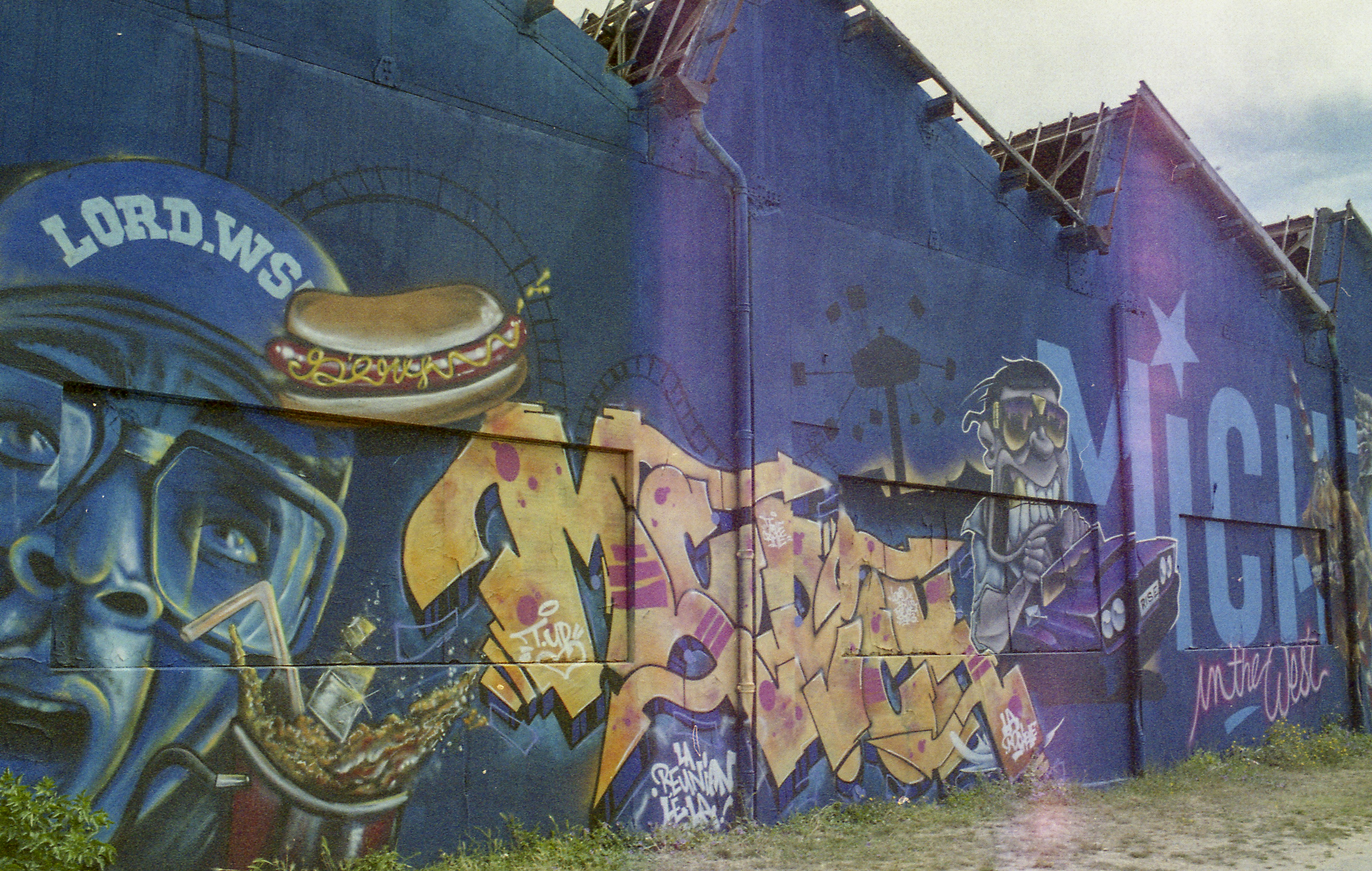 Graffiti art covers a weathered blue building wall.