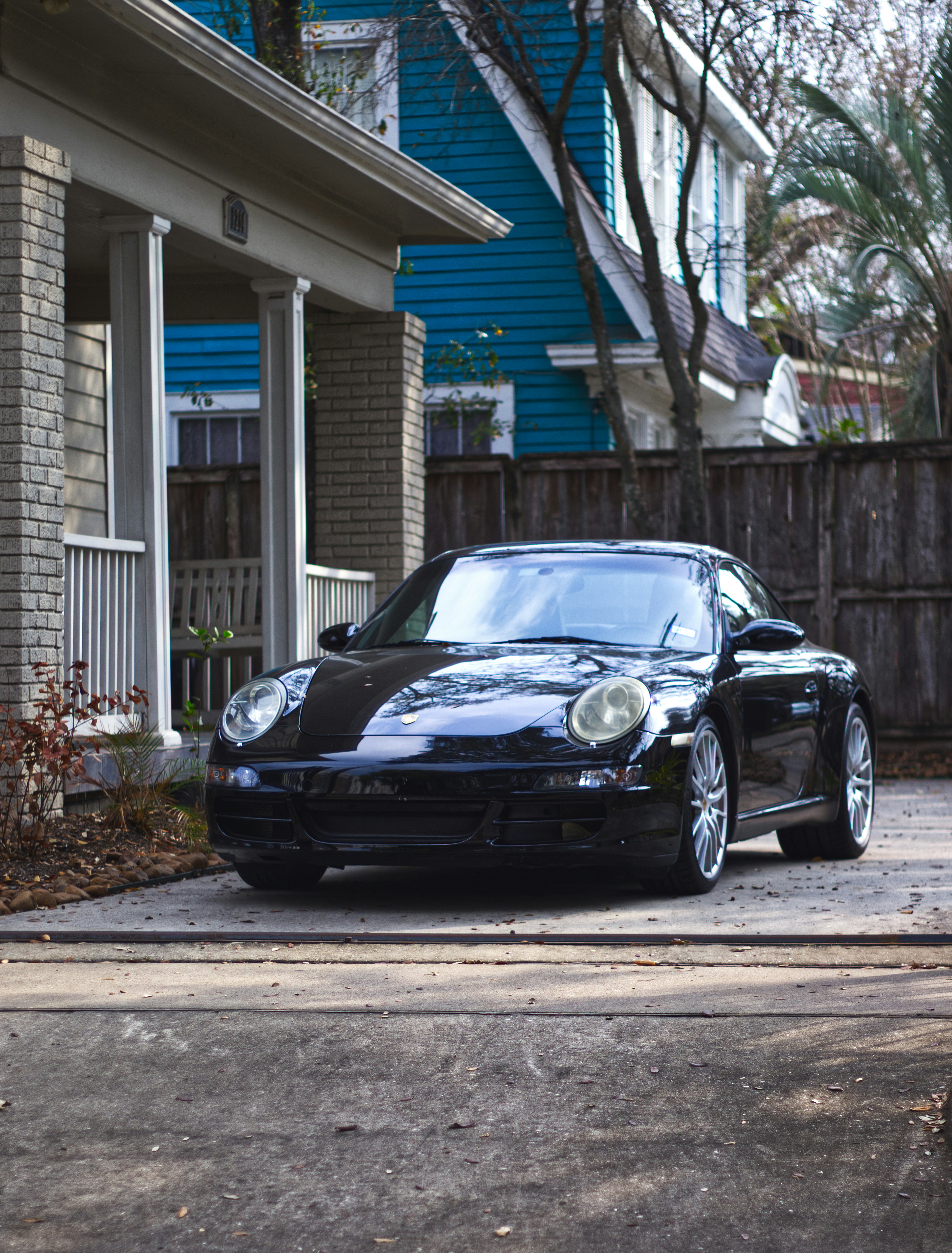 Midday Steel: A Black Porsche Nestled in a Suburban Drive