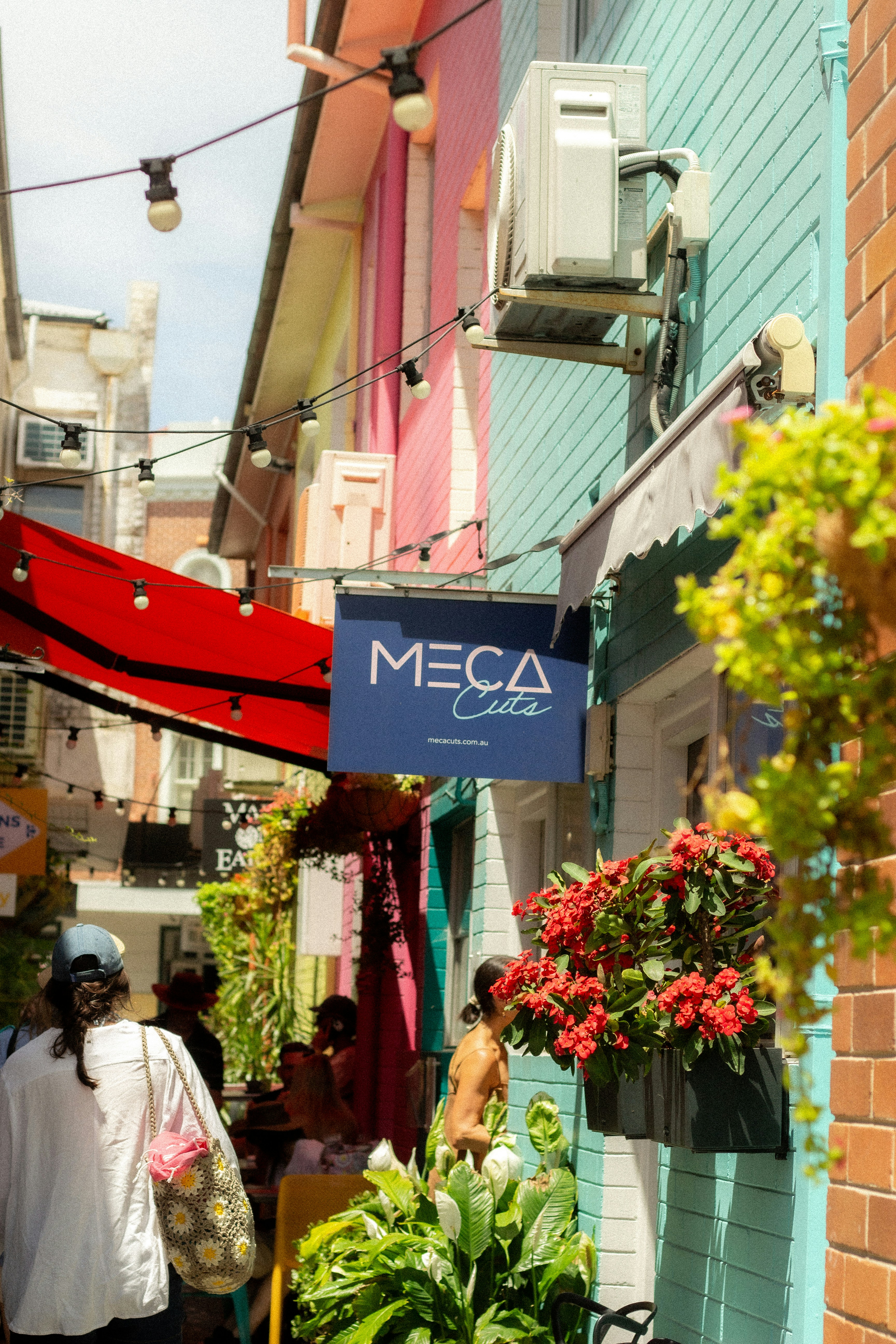 Colorful Street Café Sign Below a Cascading Sunlit Balcony