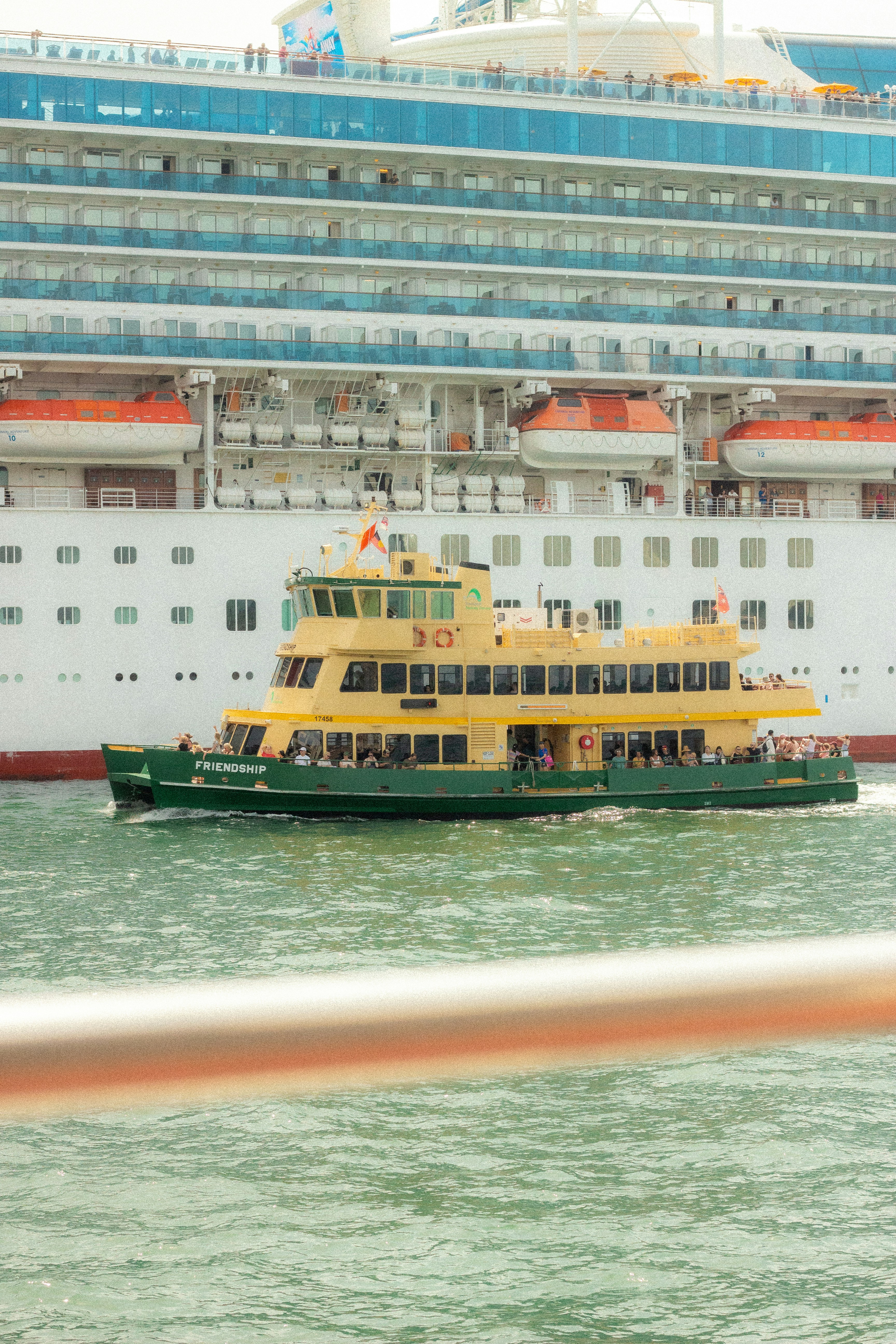 Friendship in the Harbor: A Green and Yellow Vessel Beside a Grand Cruise Ship