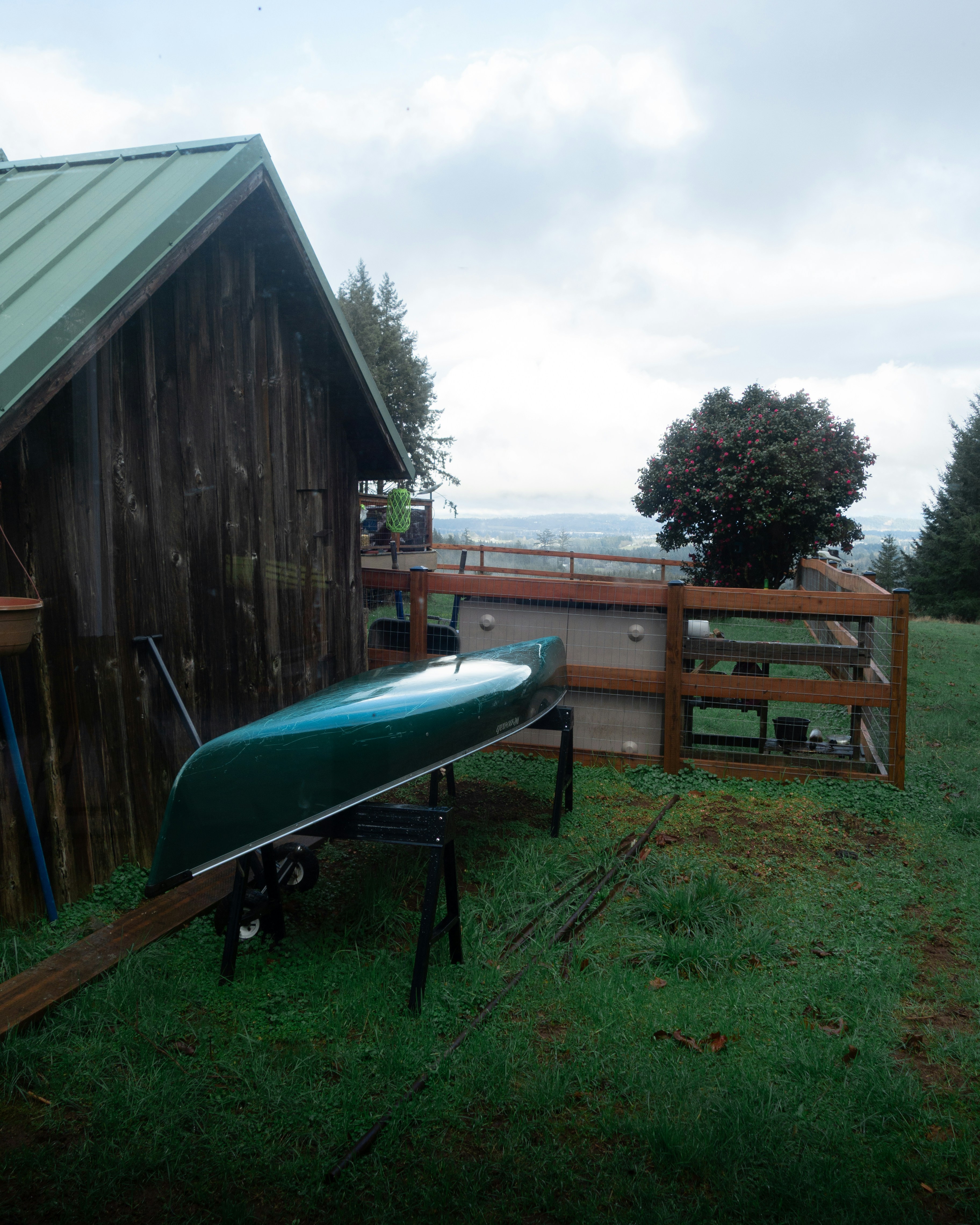 Green canoe resting on a stand near wooden shed