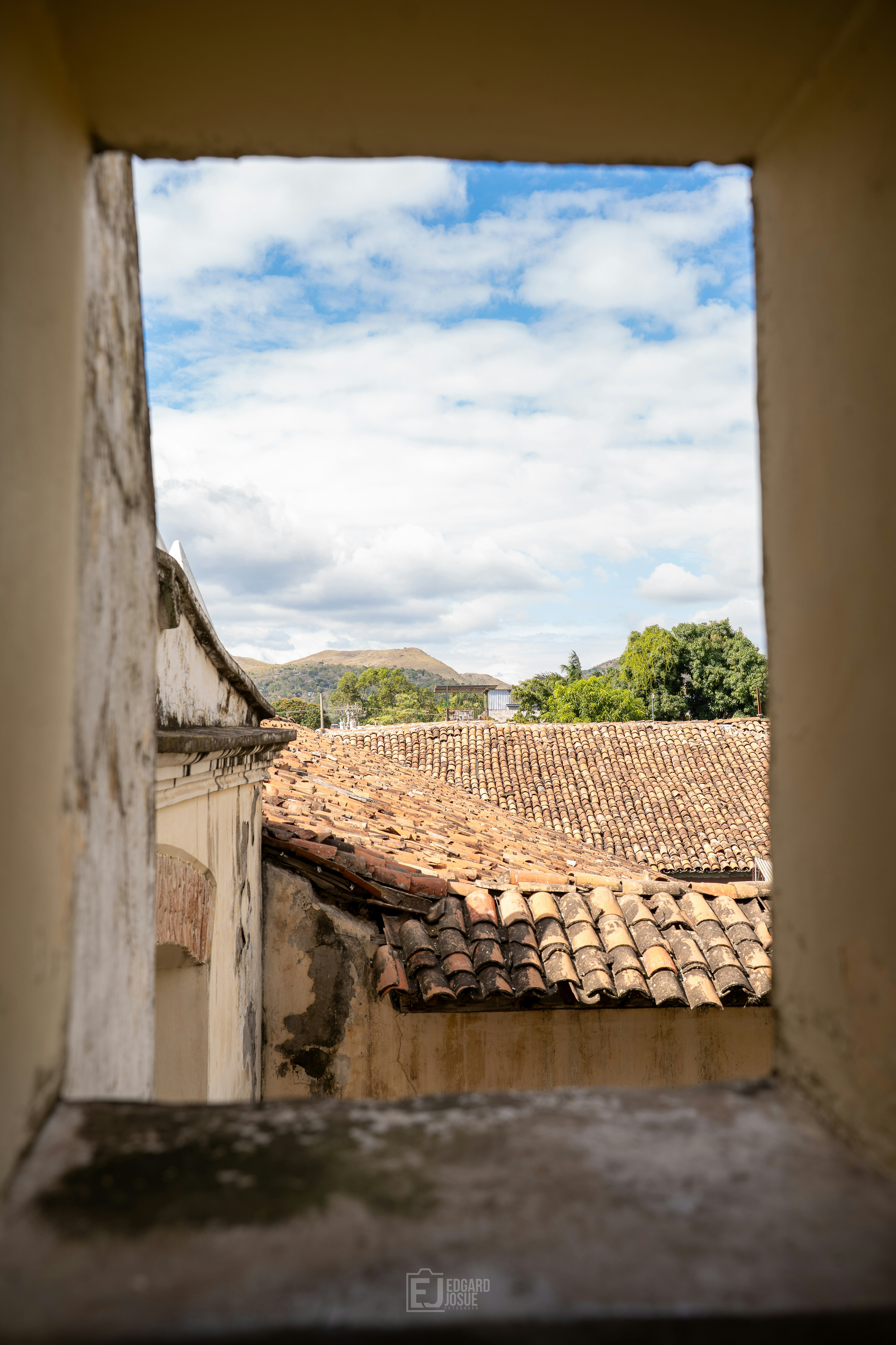 Vantage Through a Quiet Arch: Rooftops and Sky