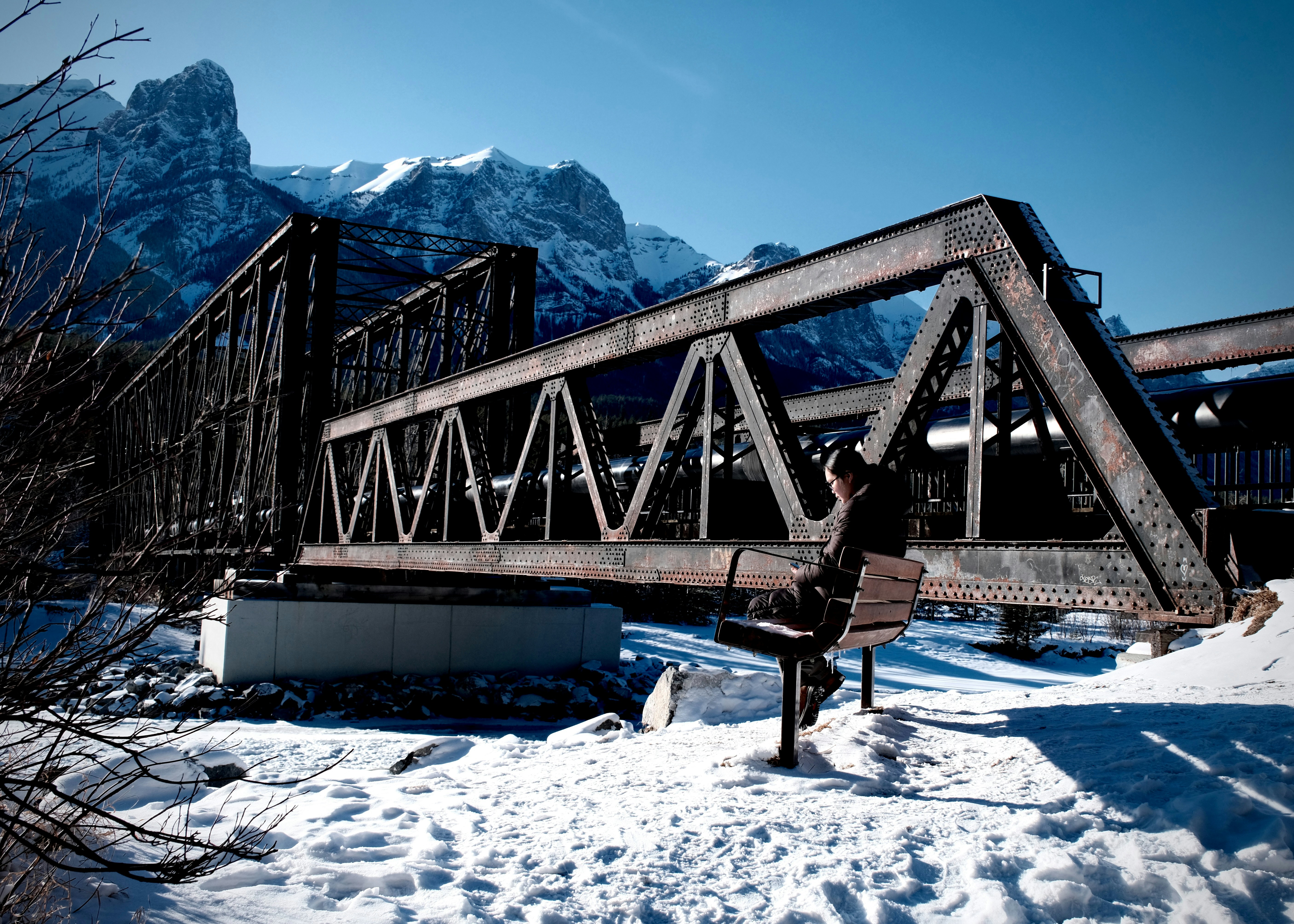Snowbound Canyon: A solitary climber Resting on an I-beam Bridge