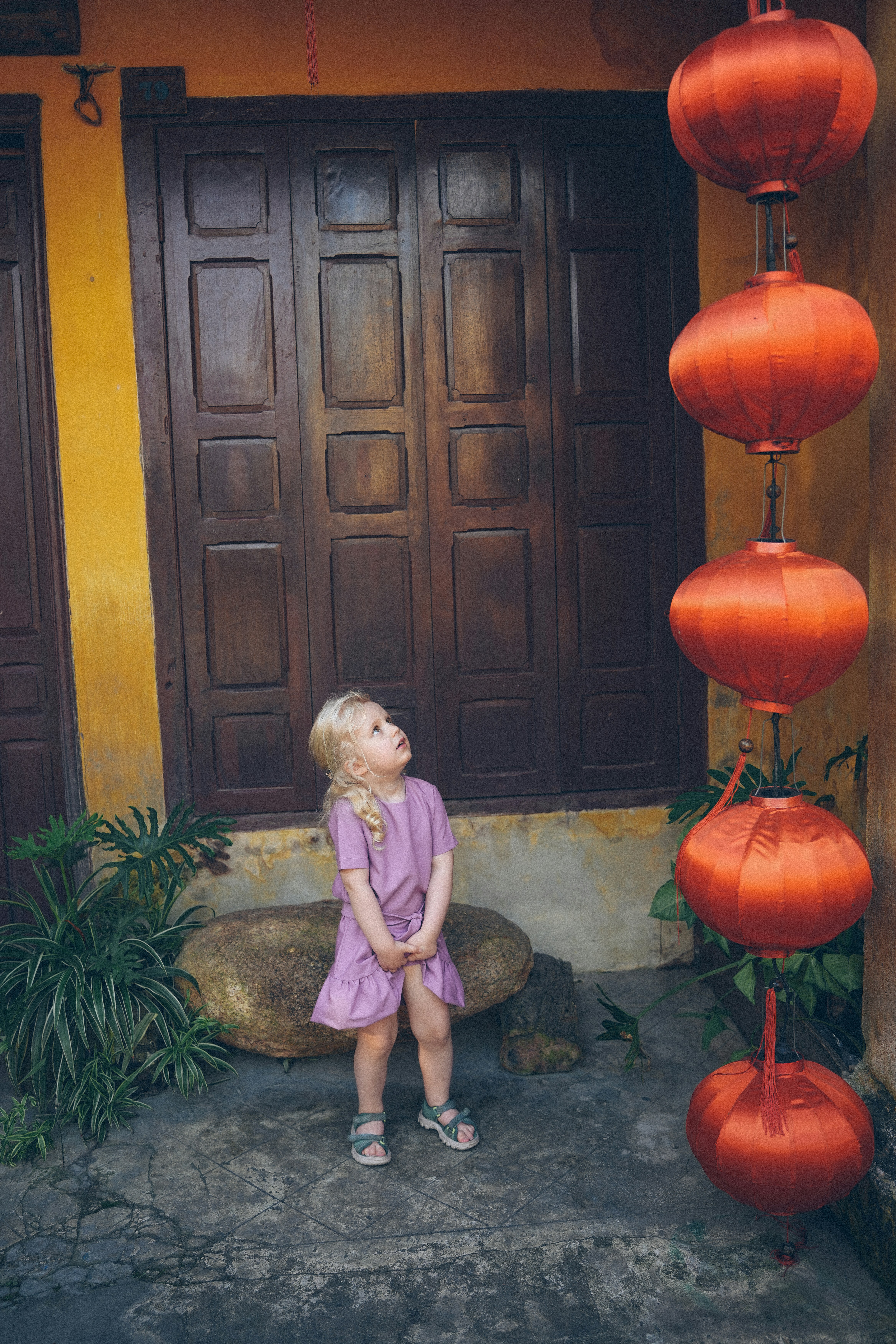 Lilac Dress and Lanterns: A Quiet Moment by the Door