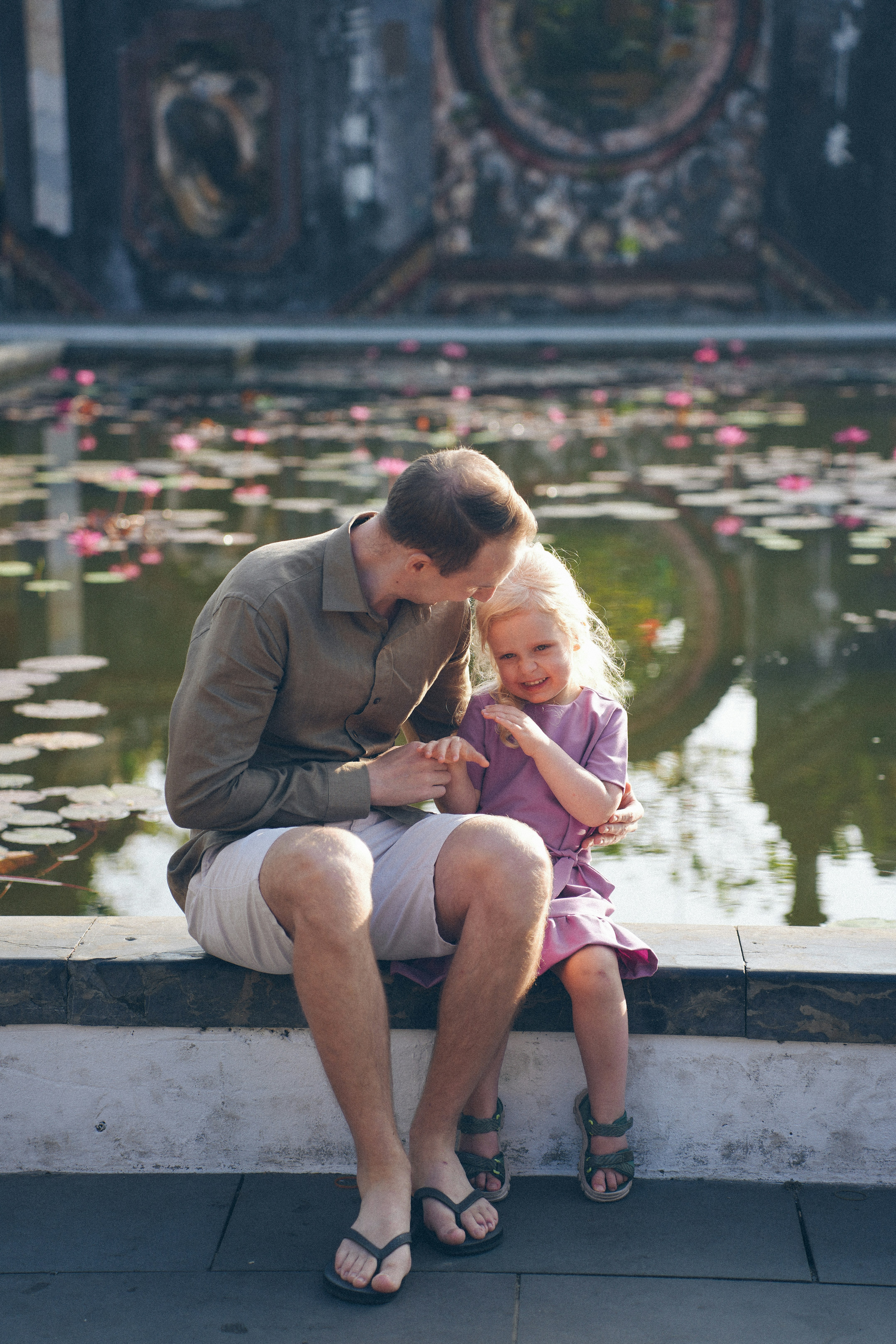 Tender Moment by the Pond: Father and Daughter Share a Quiet Kiss