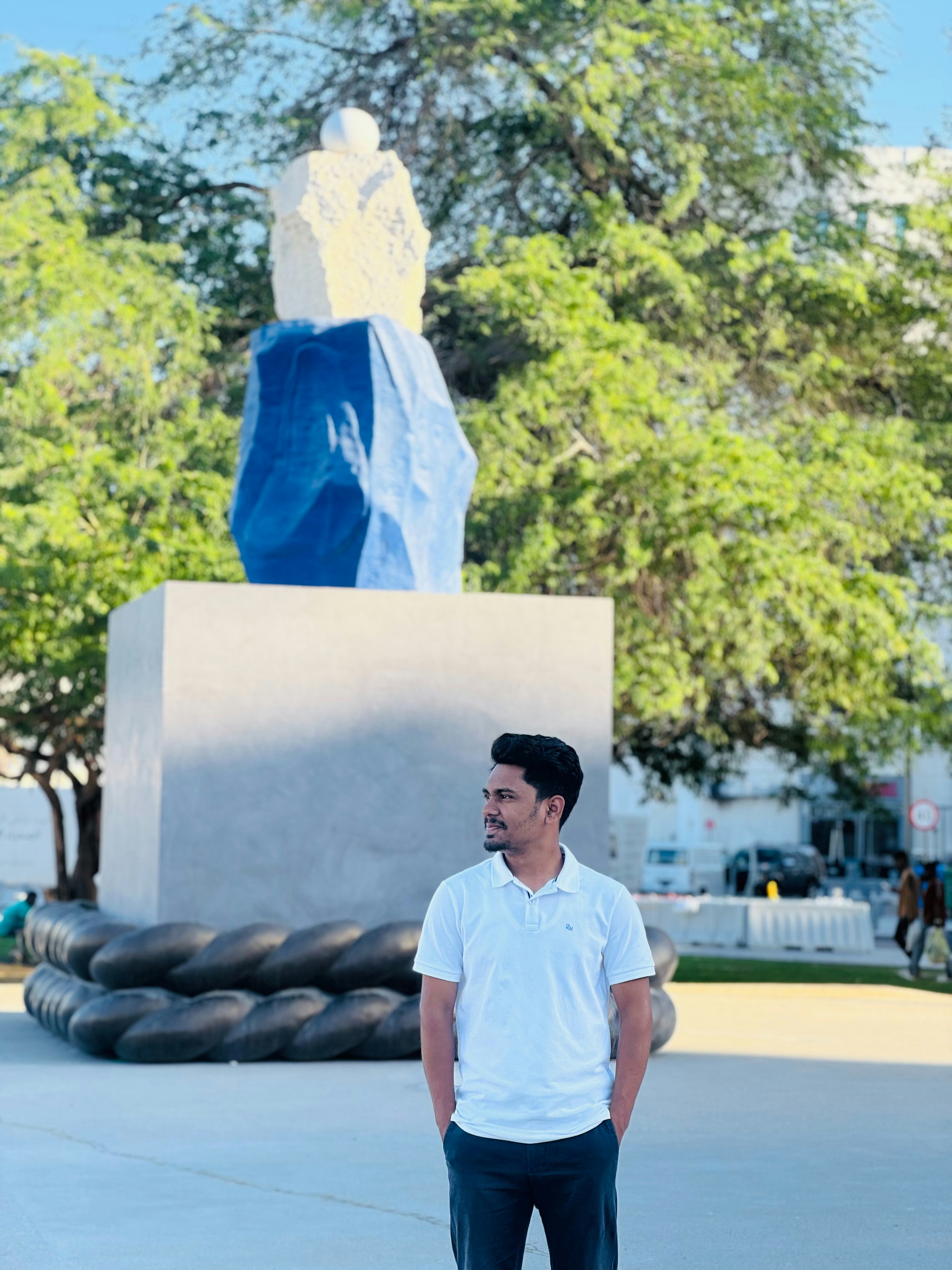 Portrait in front of a sculptural statue: a casual moment in a sunlit plaza