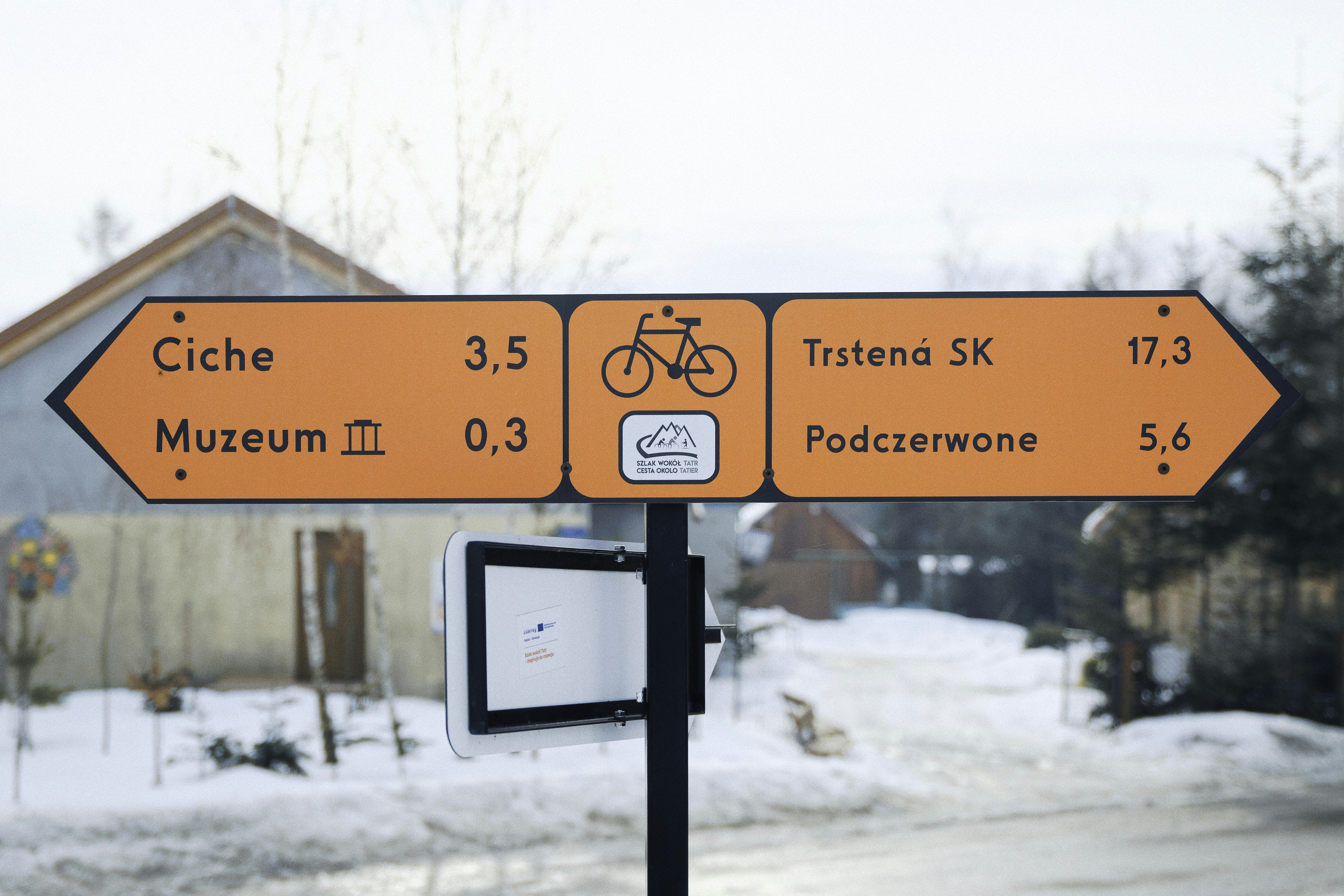 Orange Trail Signpost in a Snowy Village