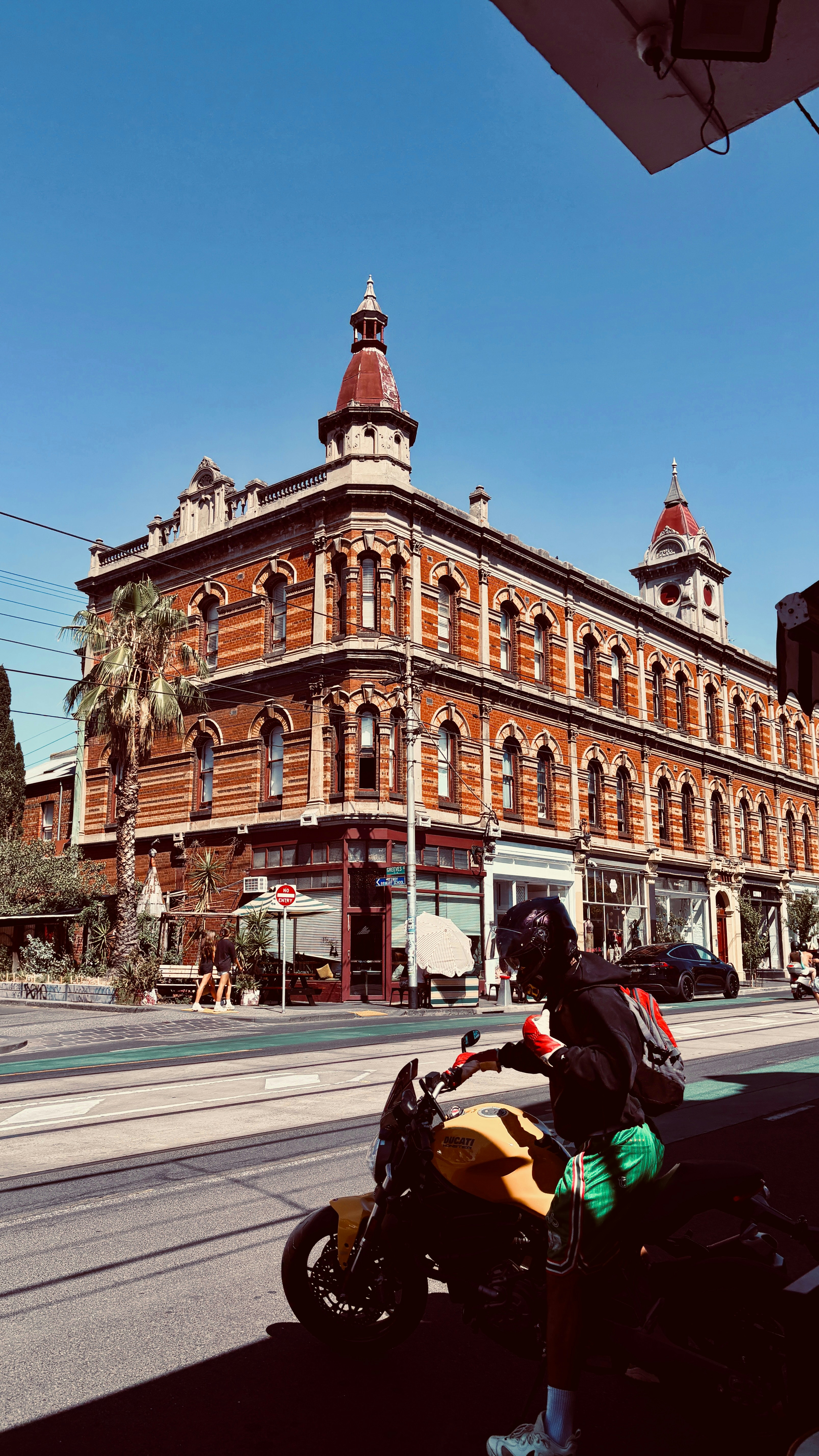 Brick‑and‑ornamented Corner, Streetcar Tracks, and a Riding Rider