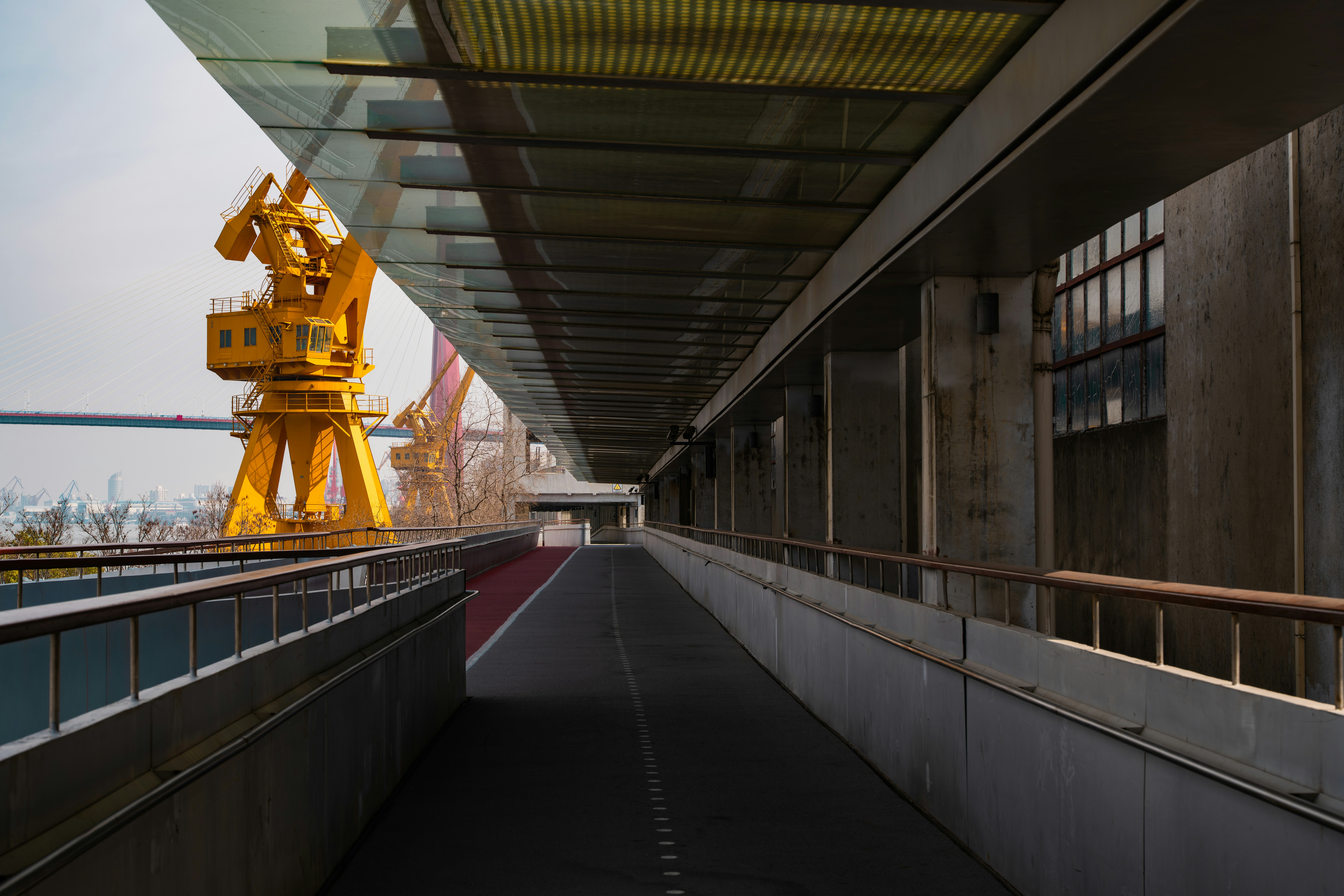 Industrial Corridor: A Yellow Crane Over a Silent Riverside Walkway