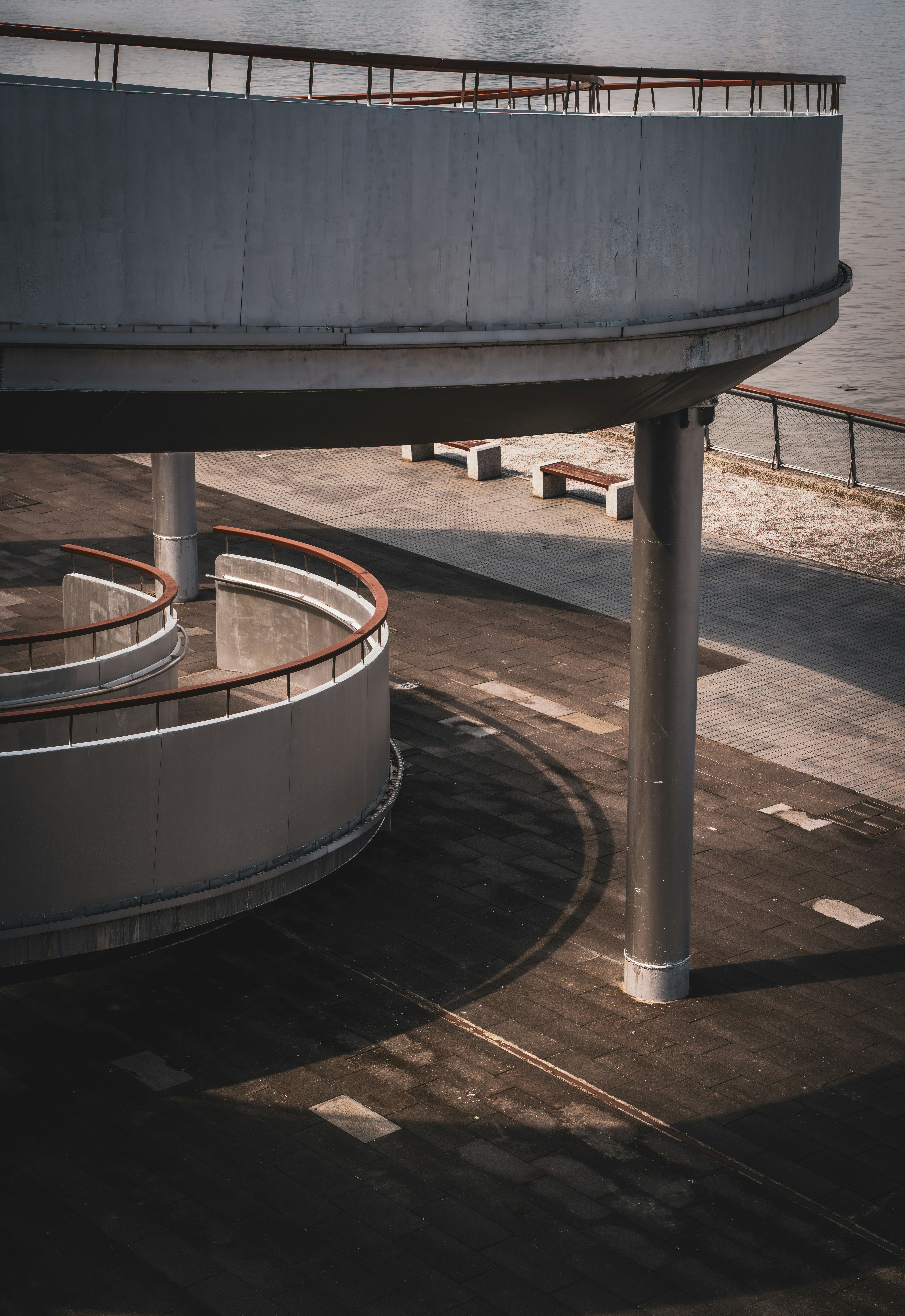 Circular ramp beneath a concrete terrace near the water