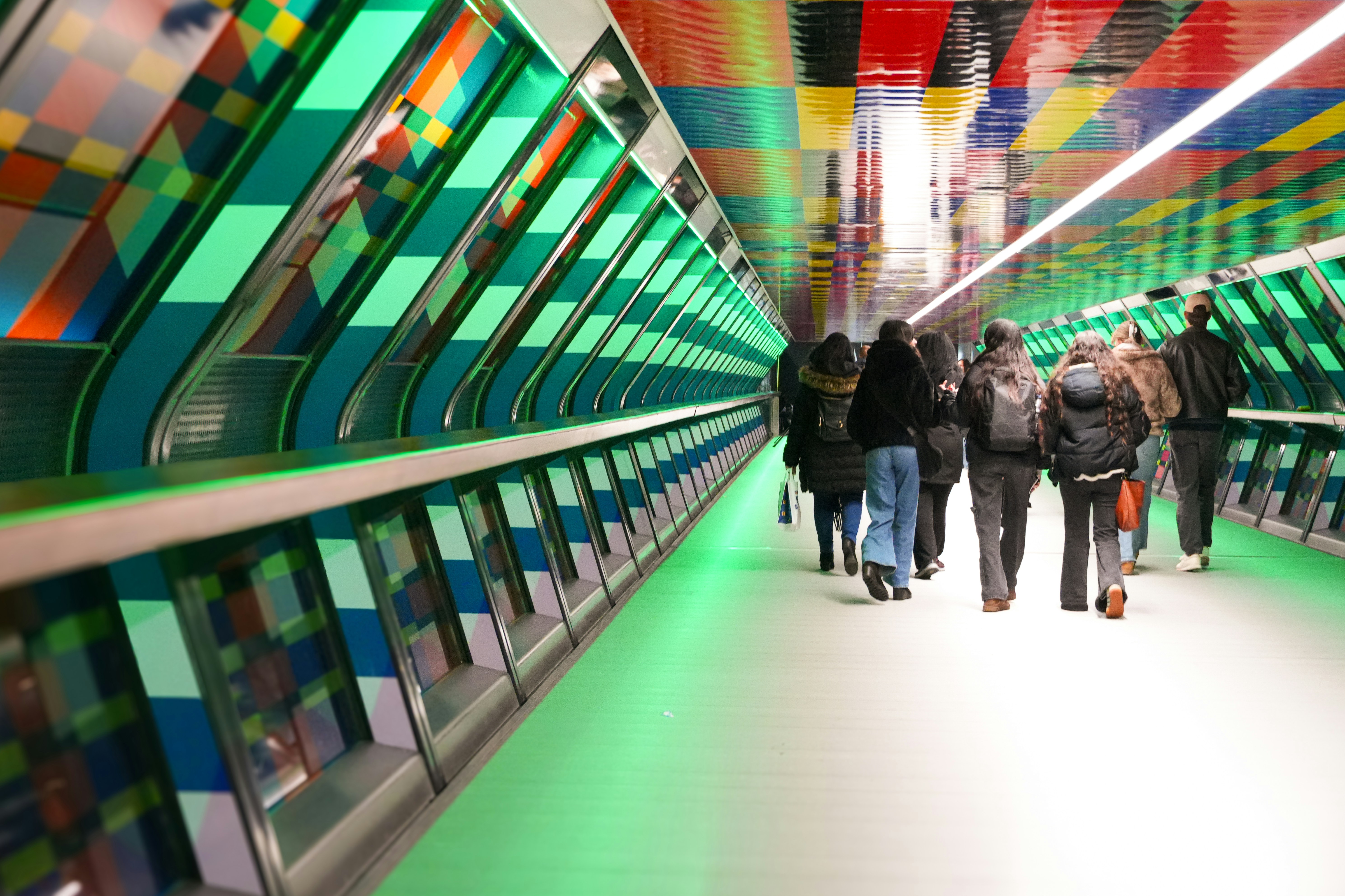 Neon Corridor: Passengers in a Colorful Metro Breeze