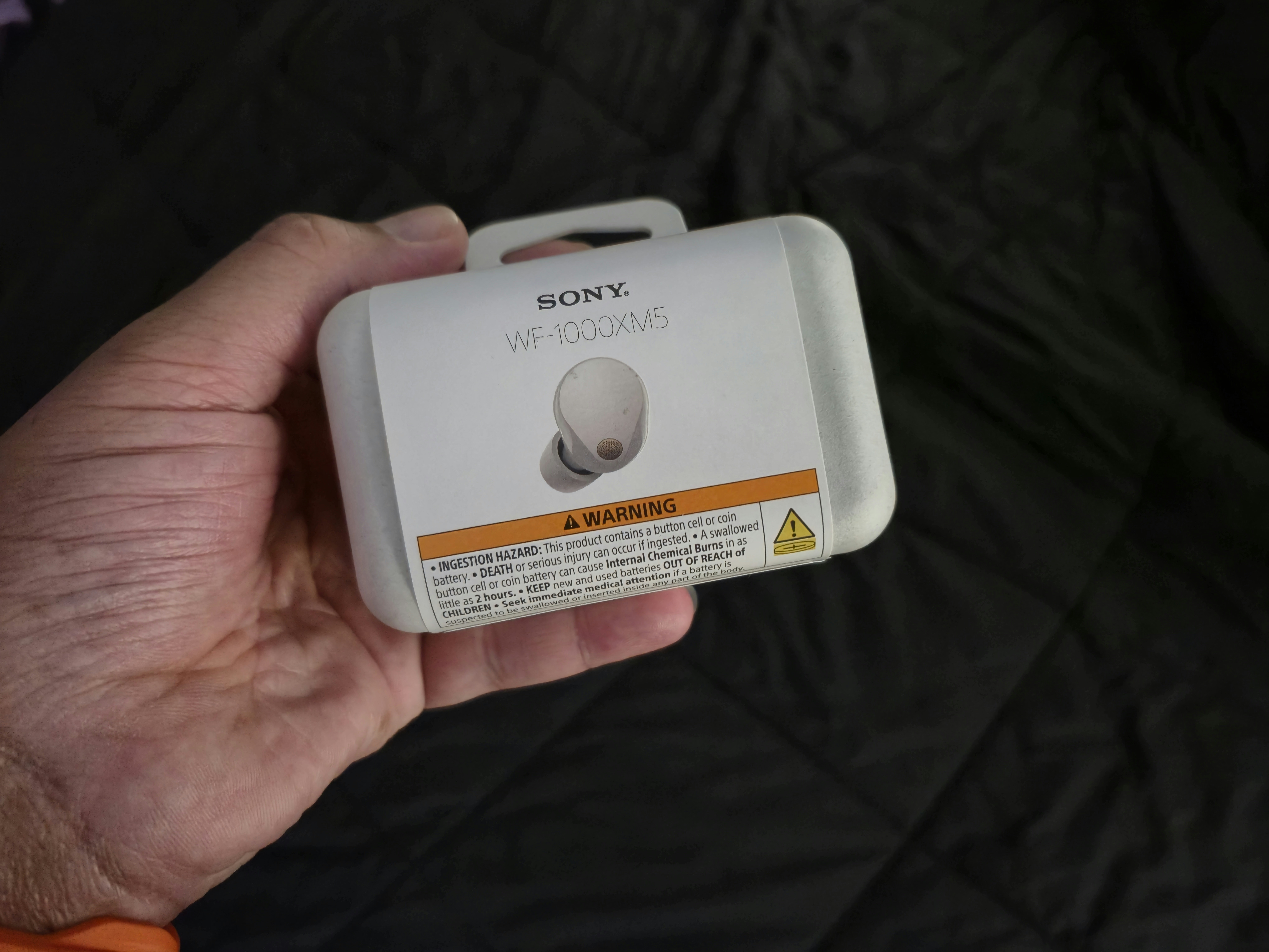 Sony earbuds in original packaging held by hand