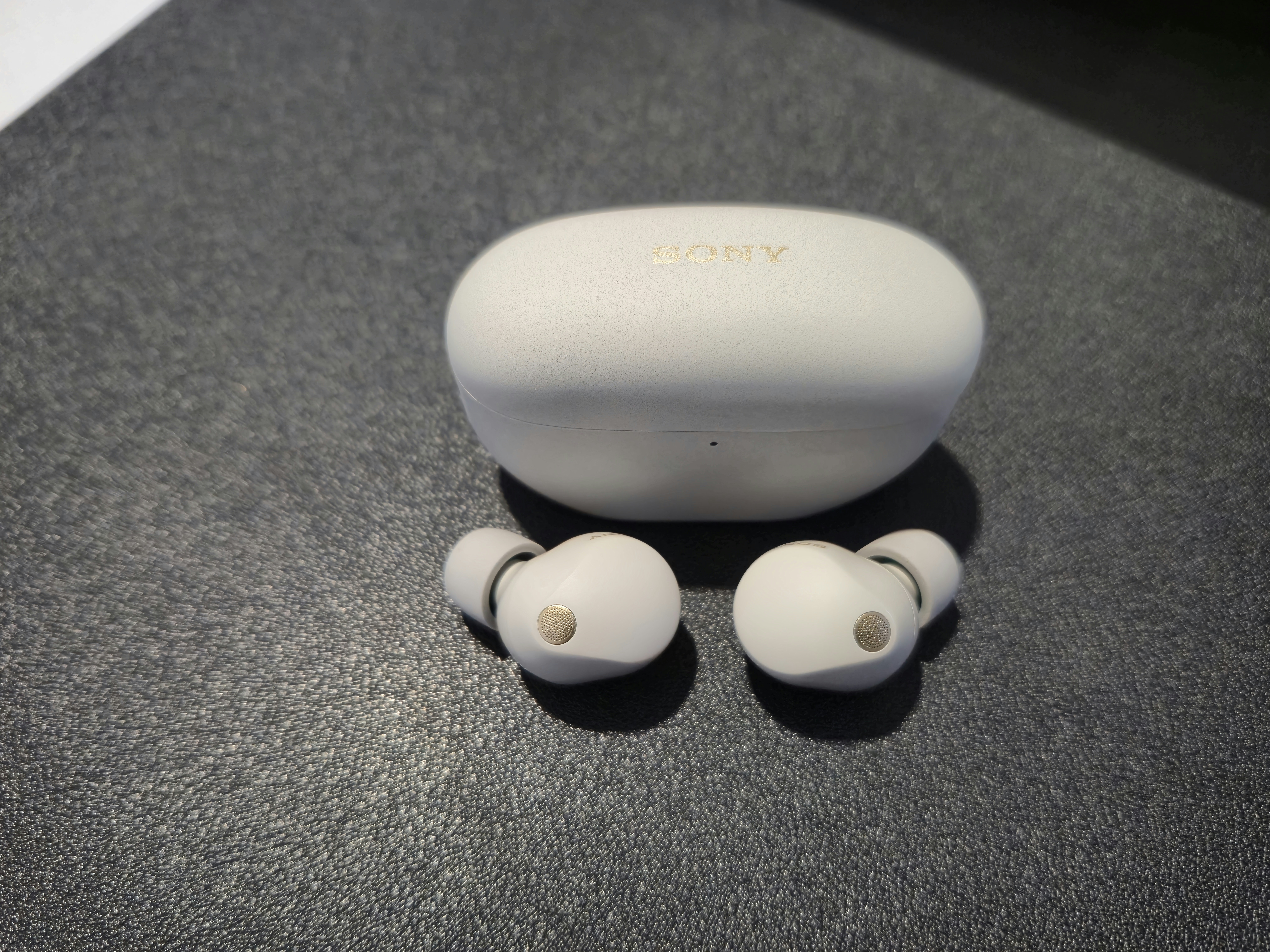 White wireless earbuds and charging case on dark surface