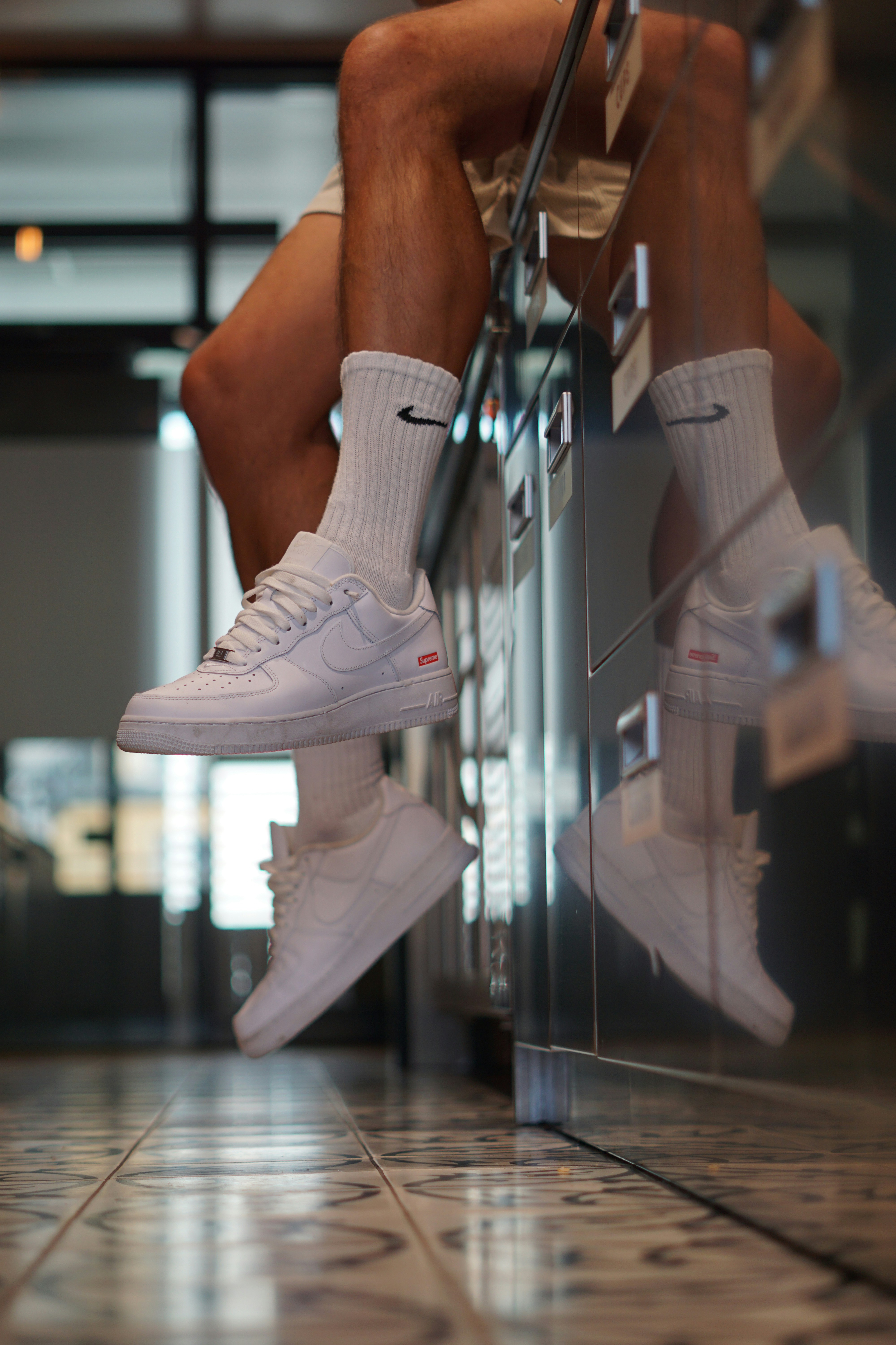 White sneakers, mirrored reflections, and tiled floor in a modern interior