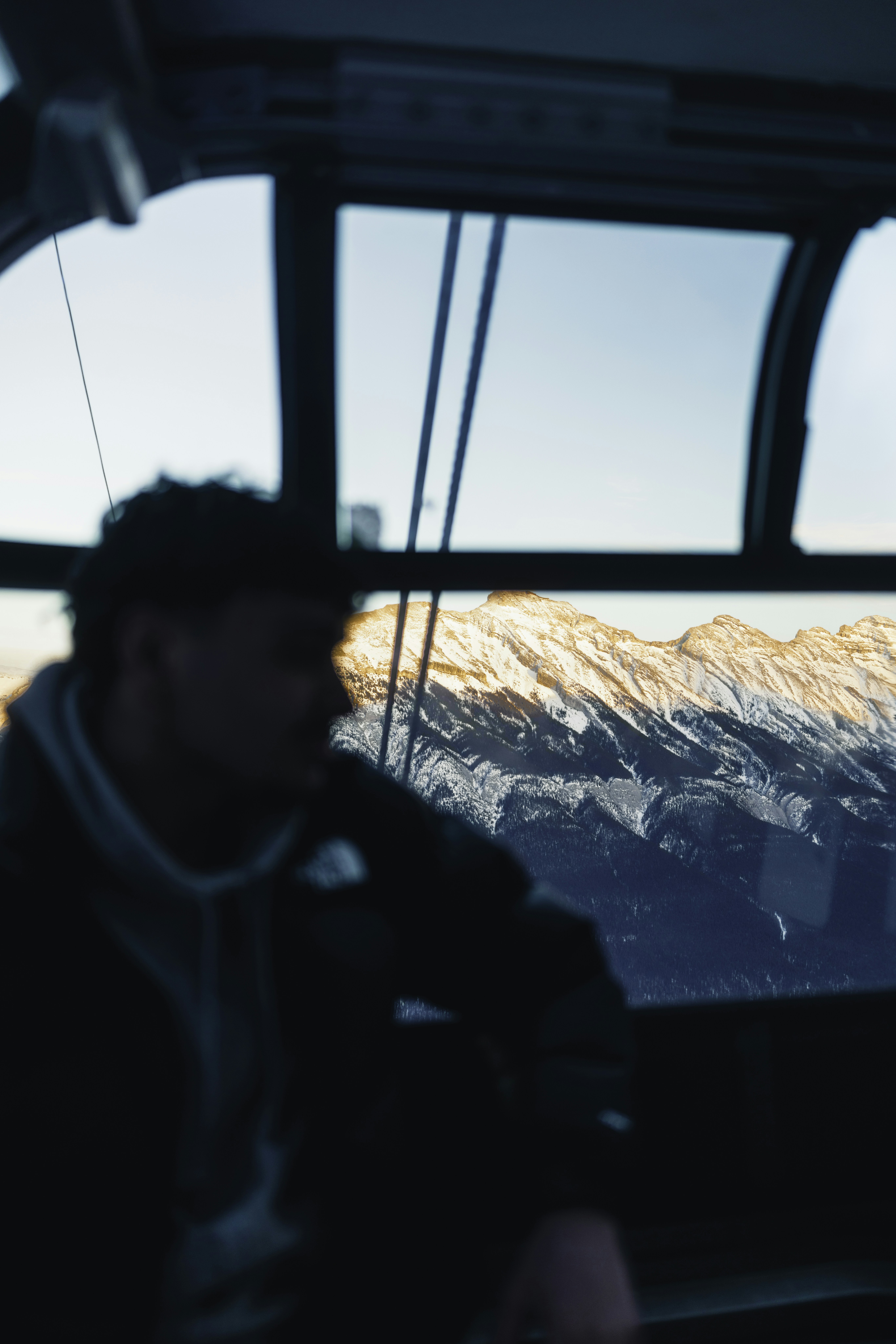 Snow-kissed peaks through a cabin window at golden hour