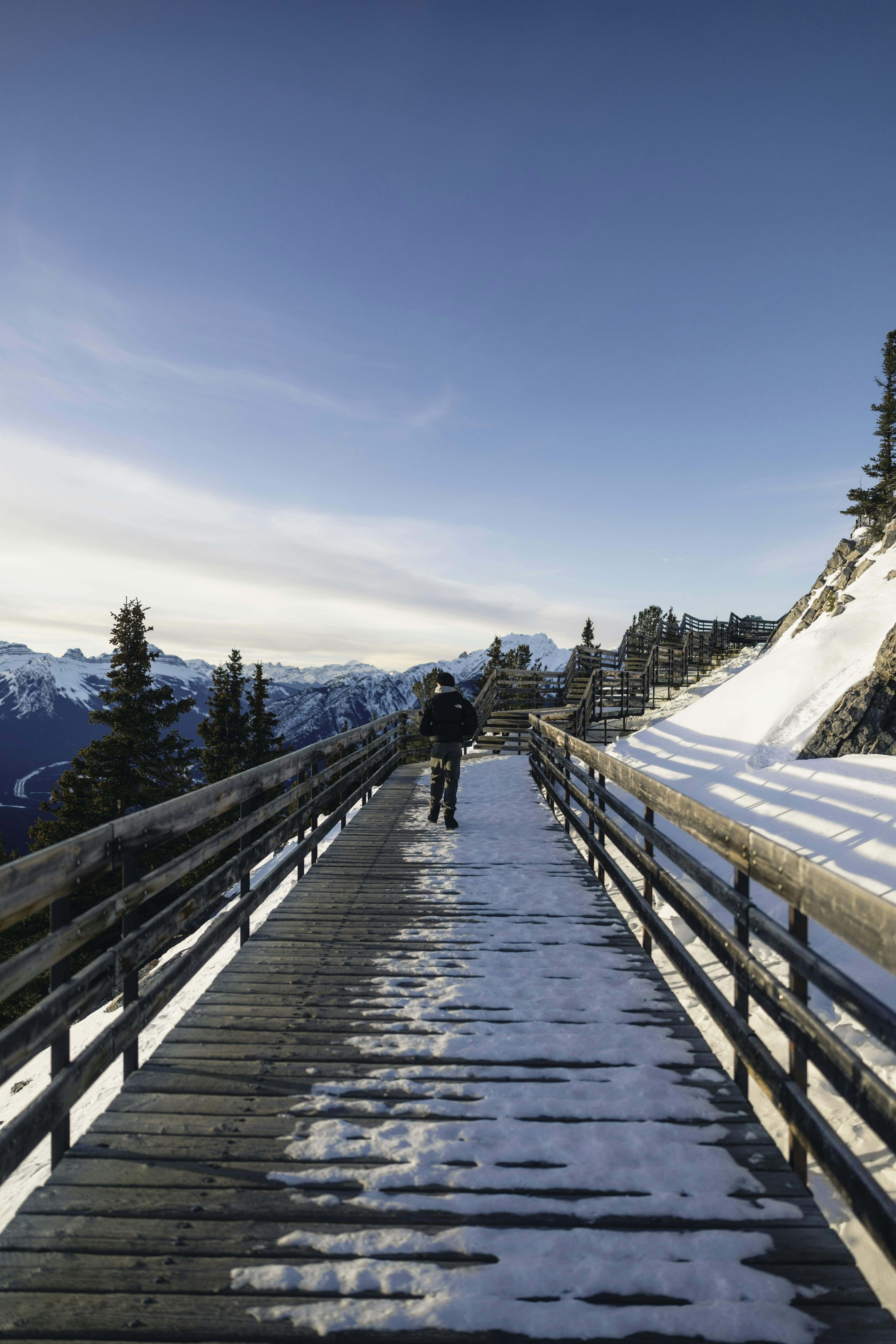 Snowbound Skywalk: A lone hiker Traverses a Mountain Planked Path