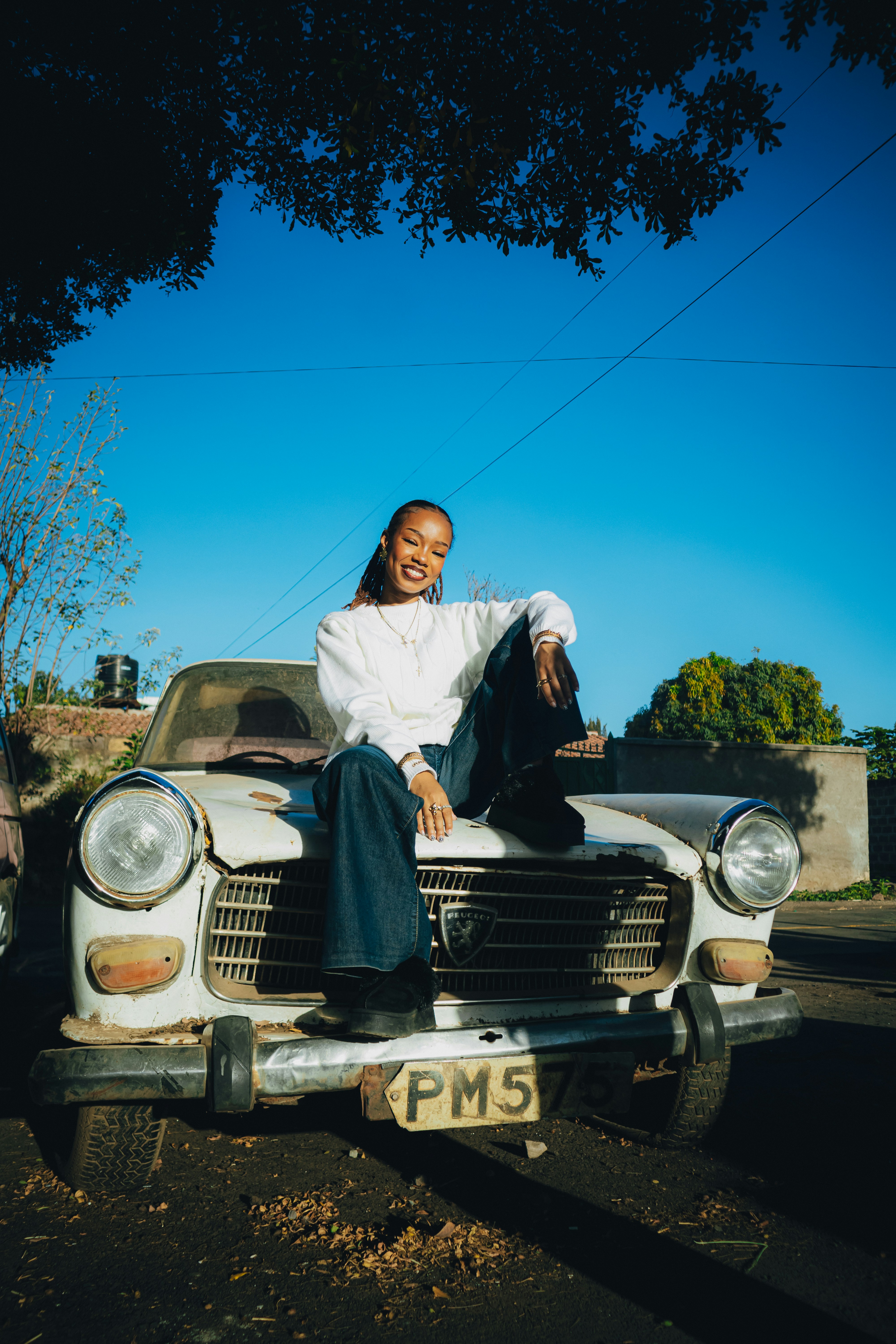 Young woman sitting on the hood of an old car.