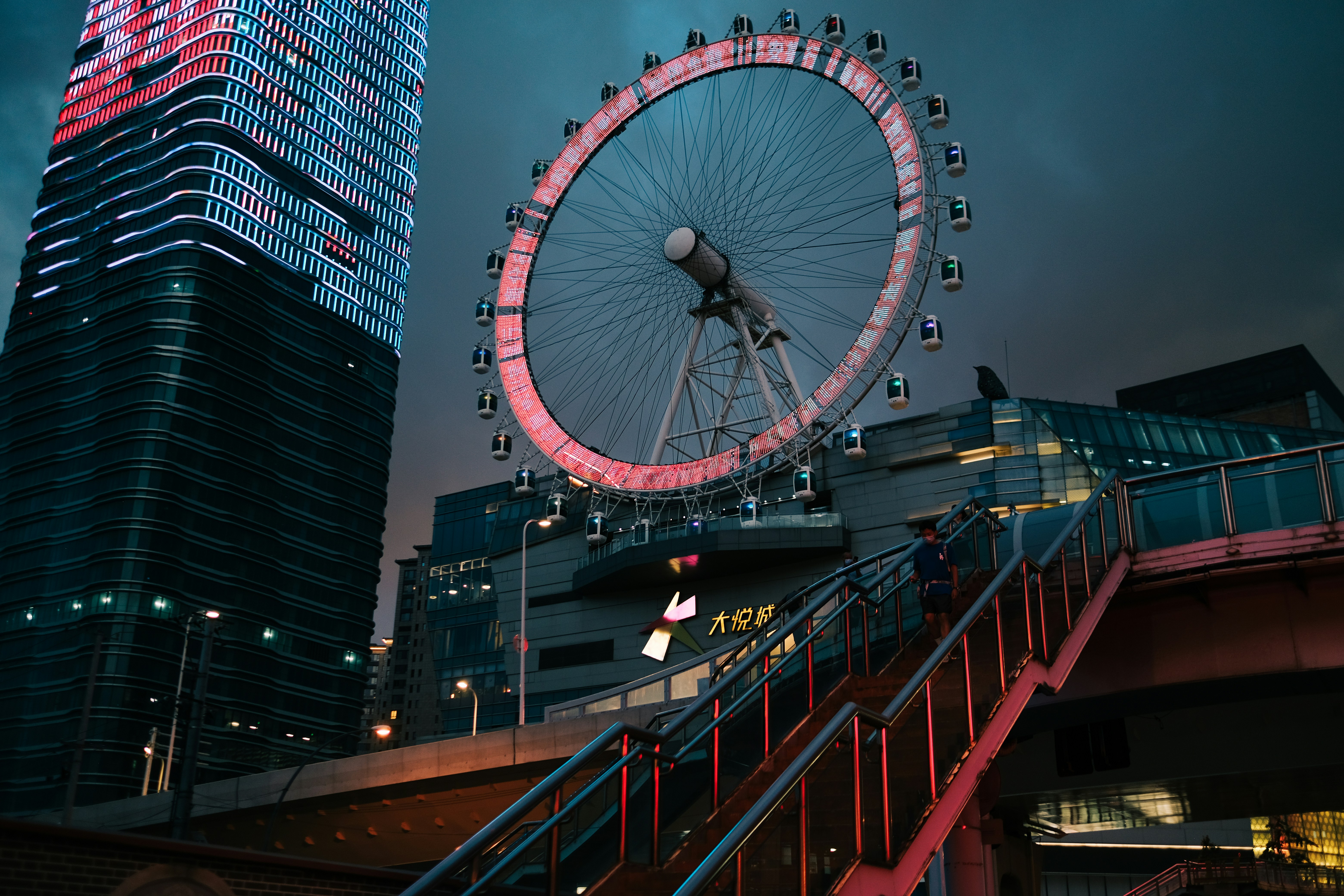 The Giant Eye of the City: A Ferris Wheel Framed Over Neon Steps