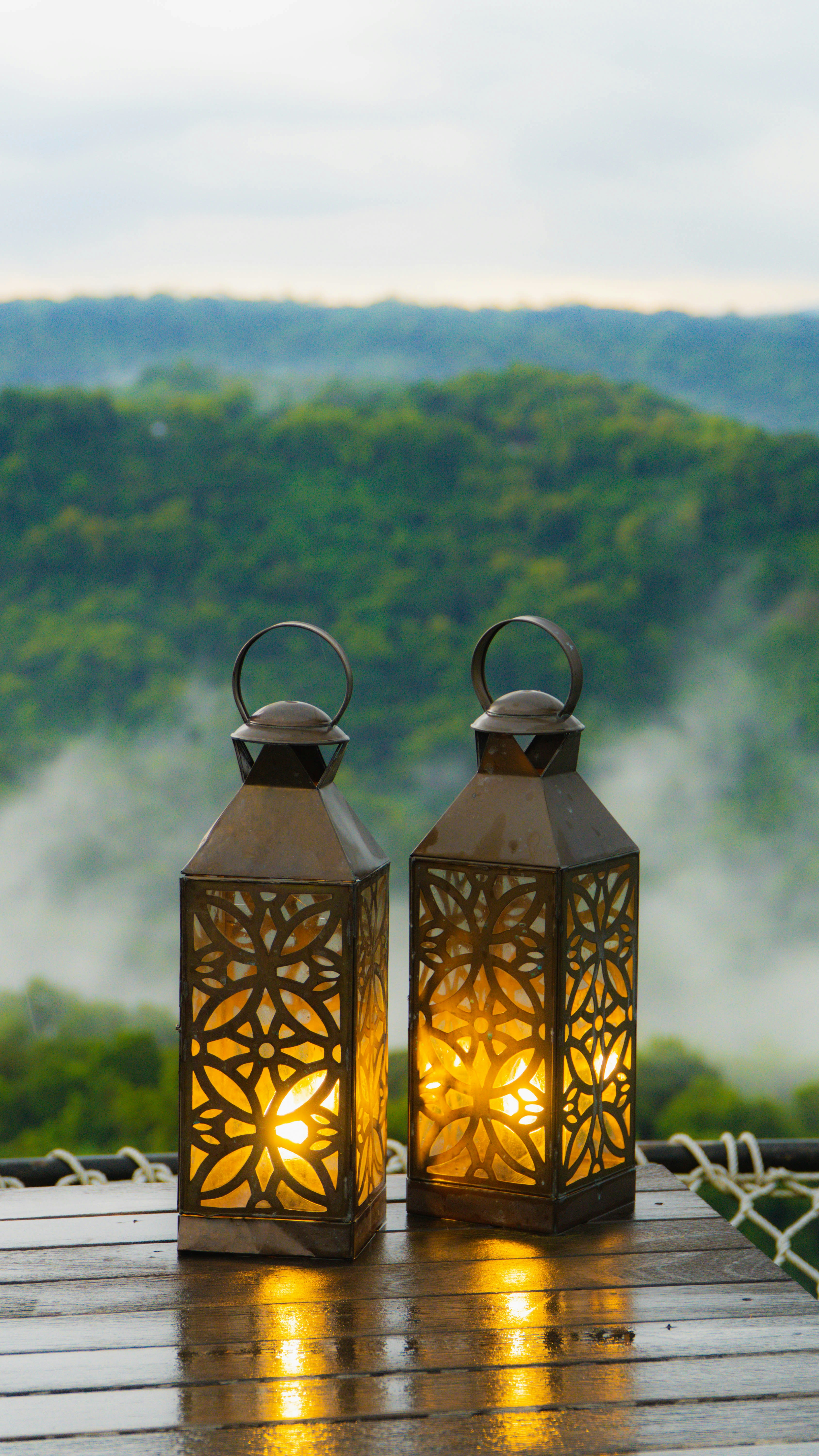 Lanterns on a Rain-Slick Deck with Misty Hills
