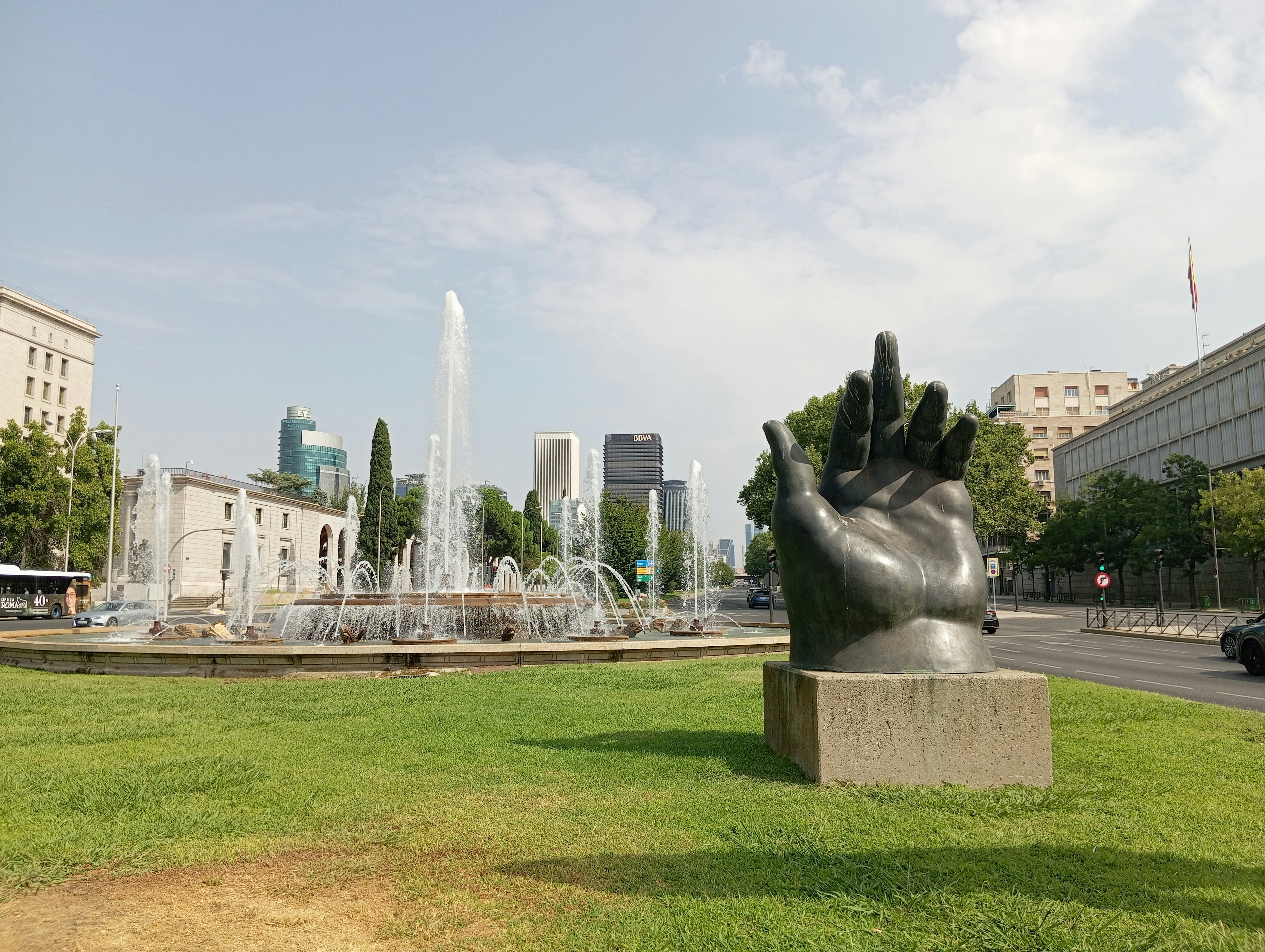 A large hand sculpture stands near a fountain.