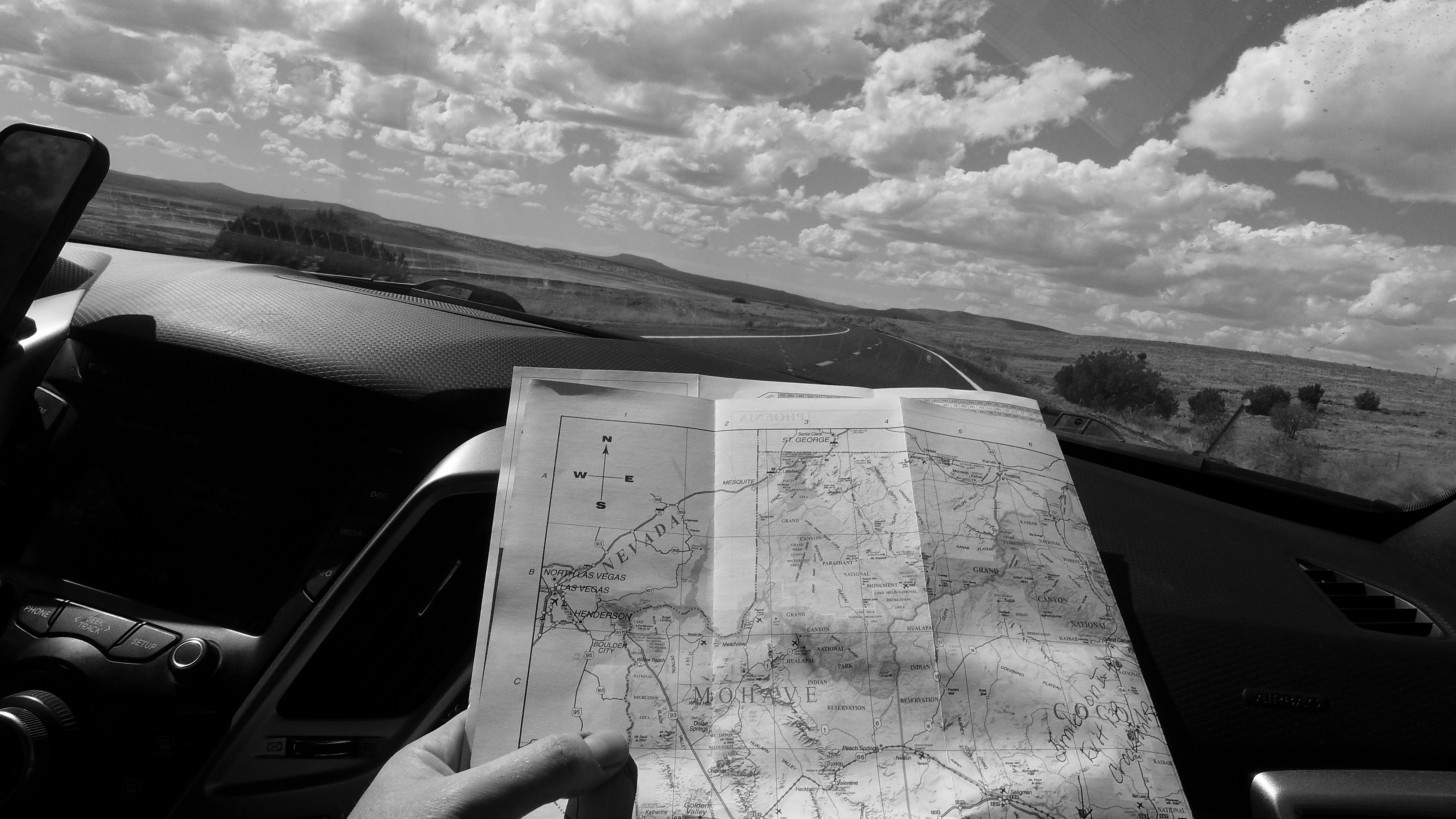 Hand holding map inside car looking at landscape