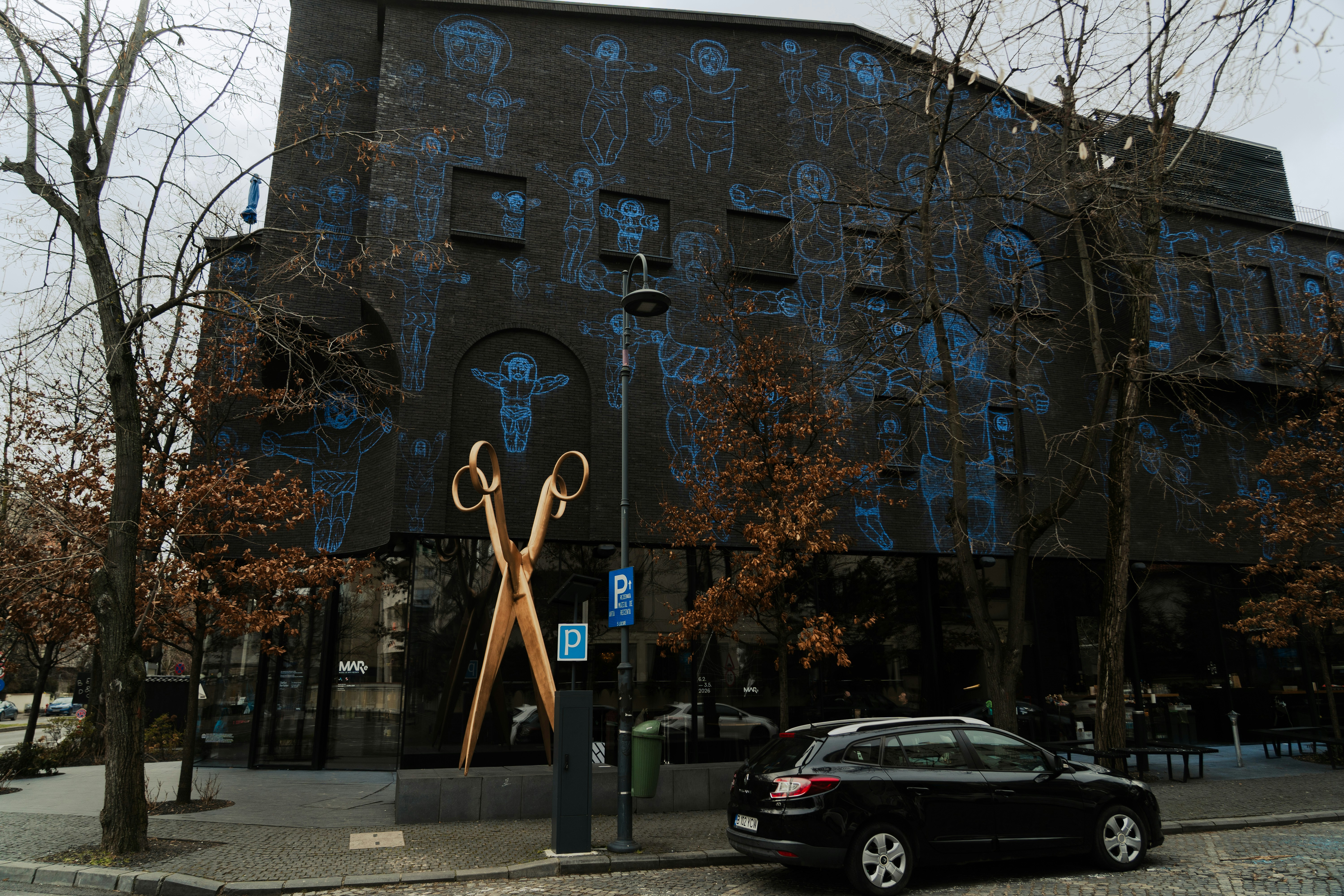 Building with large scissors sculpture and blue art