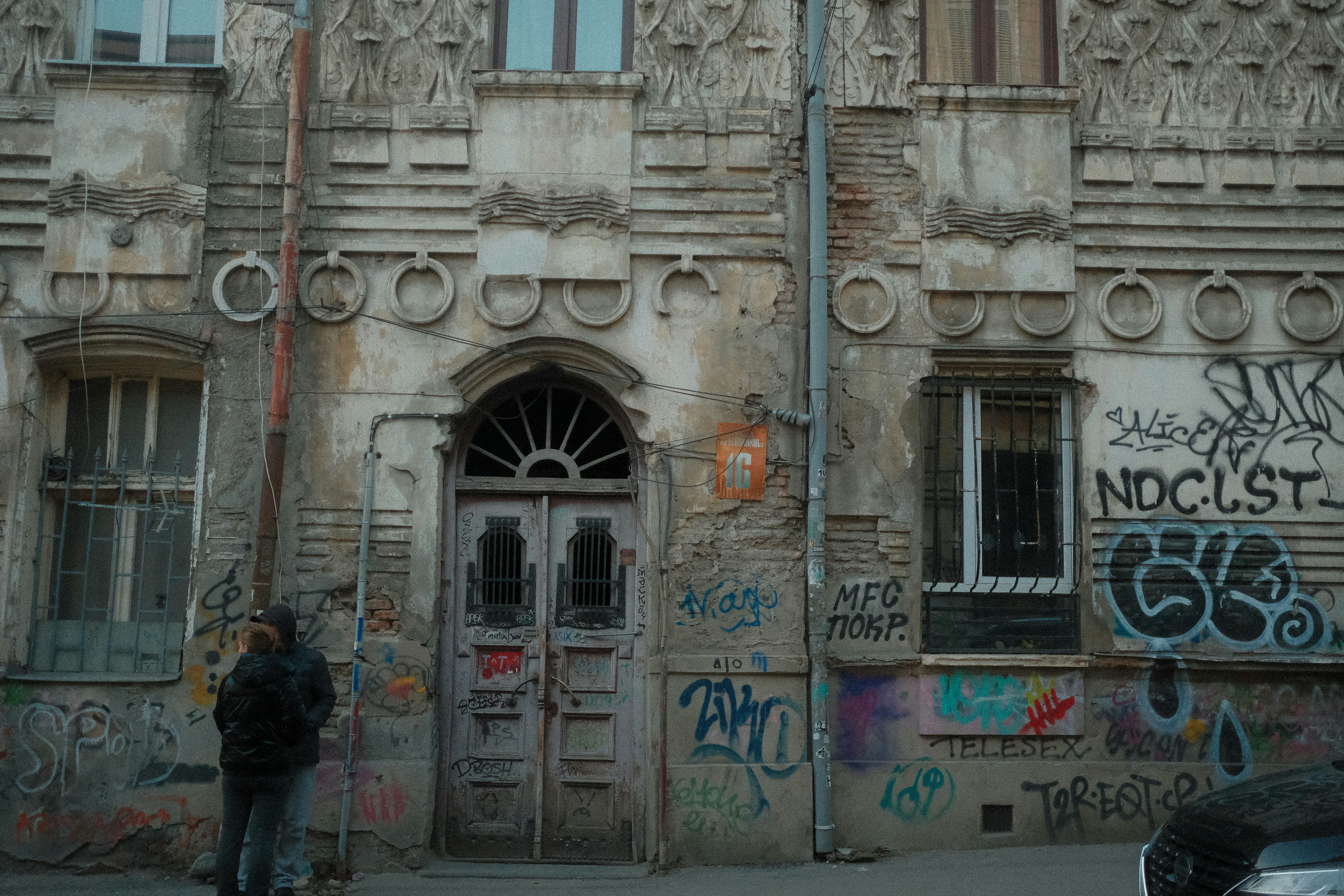 Graffiti-Faded Facade: A Stranger in an Alley of Painted Walls