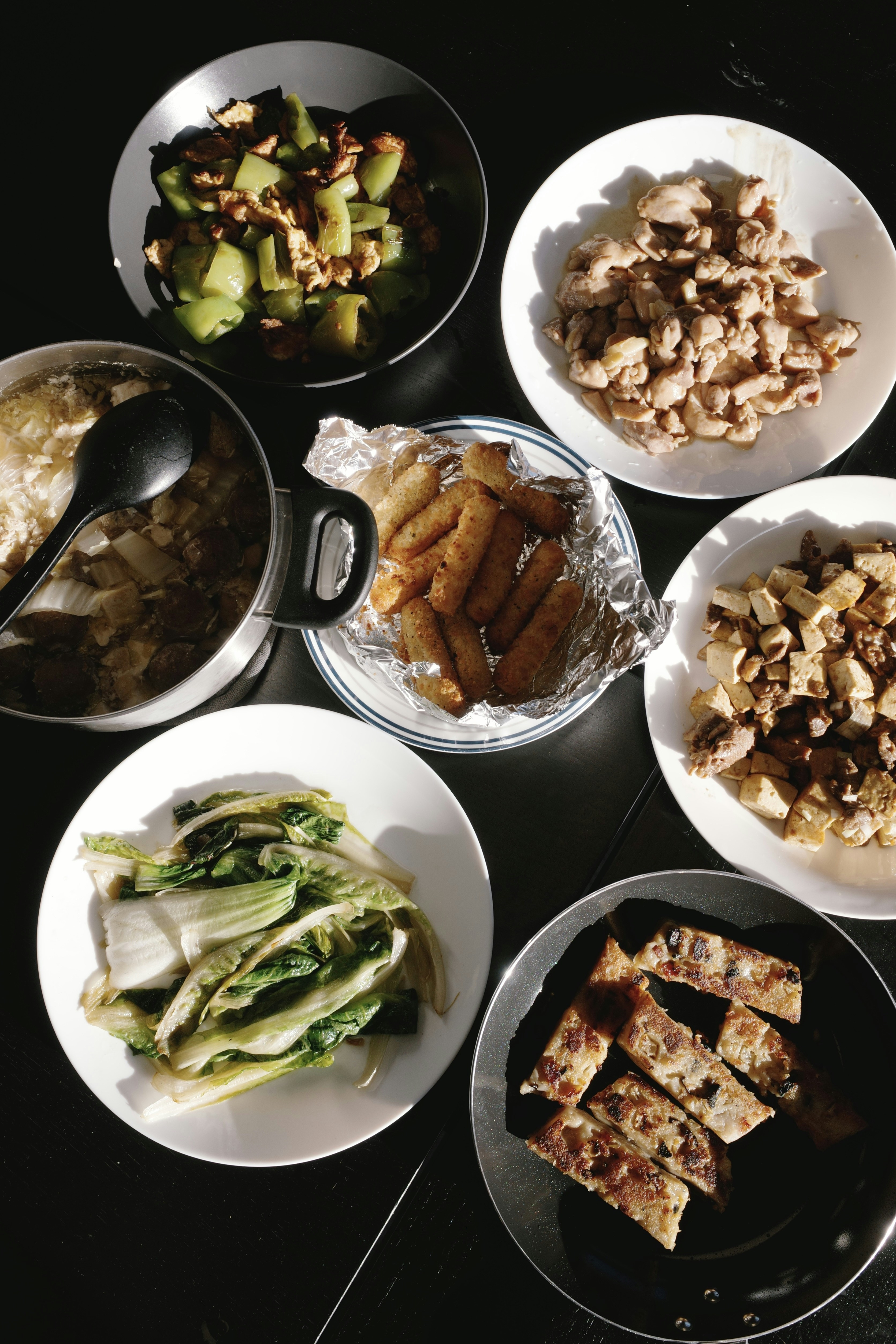 A spread of various asian dishes on a dark table.