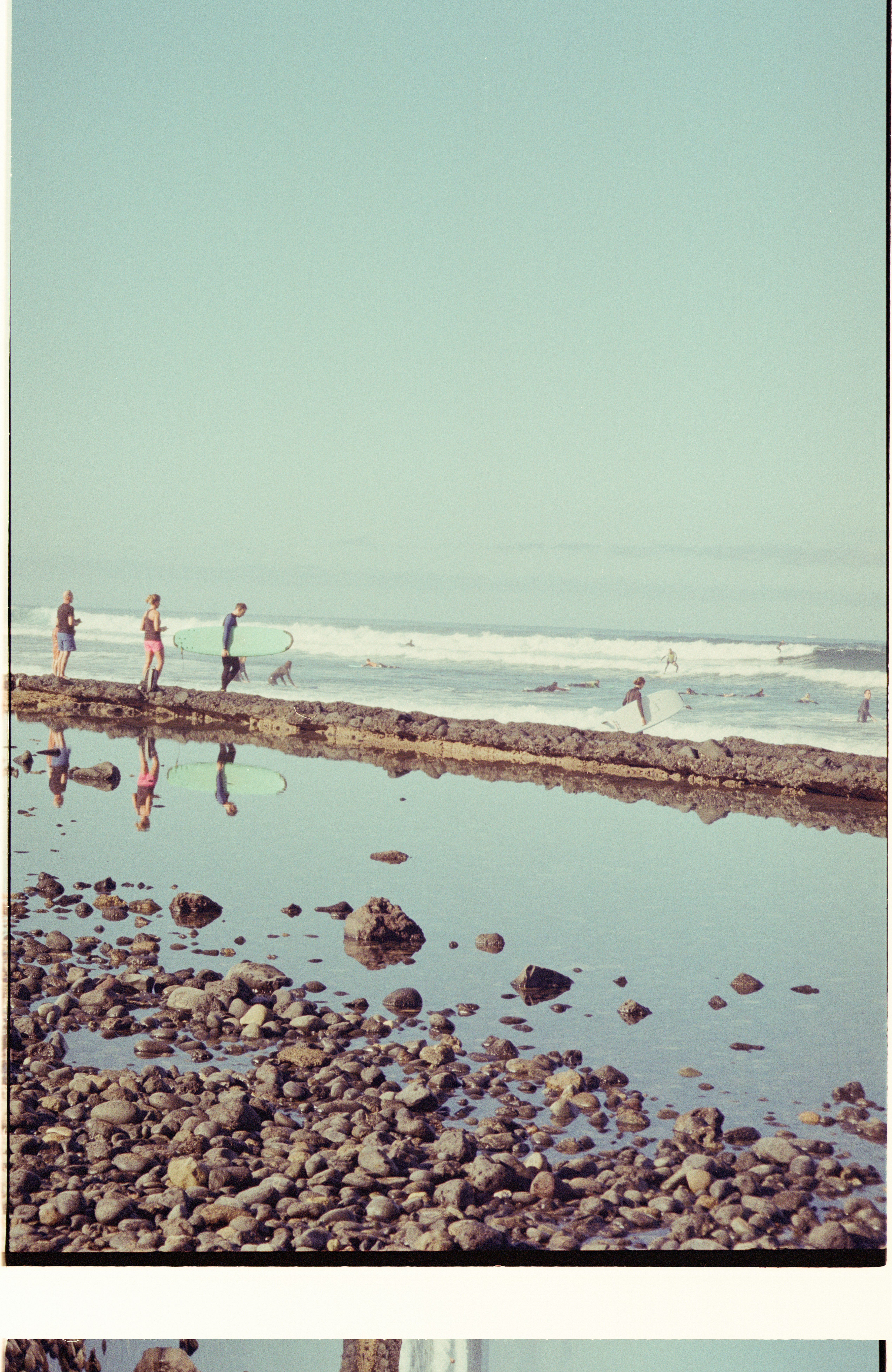 Coastal Silhouettes: Surf Trainers and Reflections on a Pebble Beach