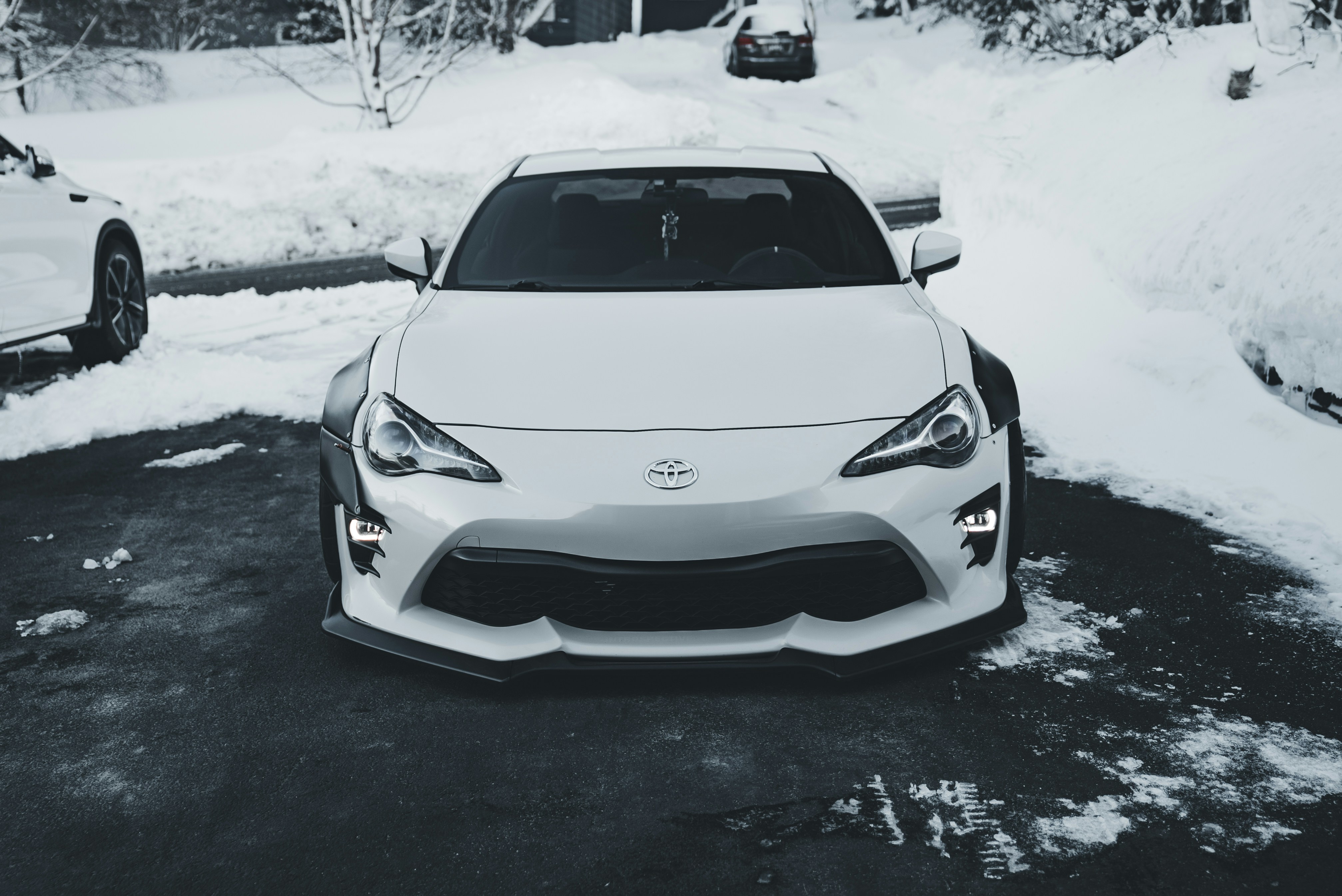 Snow-Blanketed Cornerstone: A White Sports Car Anchors a Quiet Parking Lot