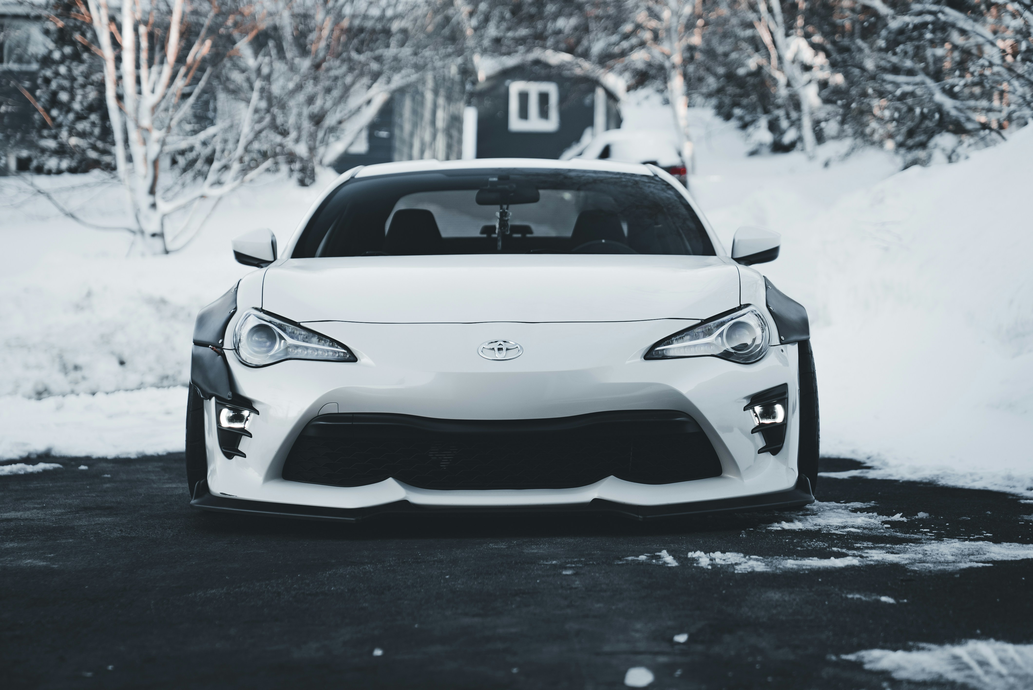 Low-slung white sports car emerges from a snowy driveway